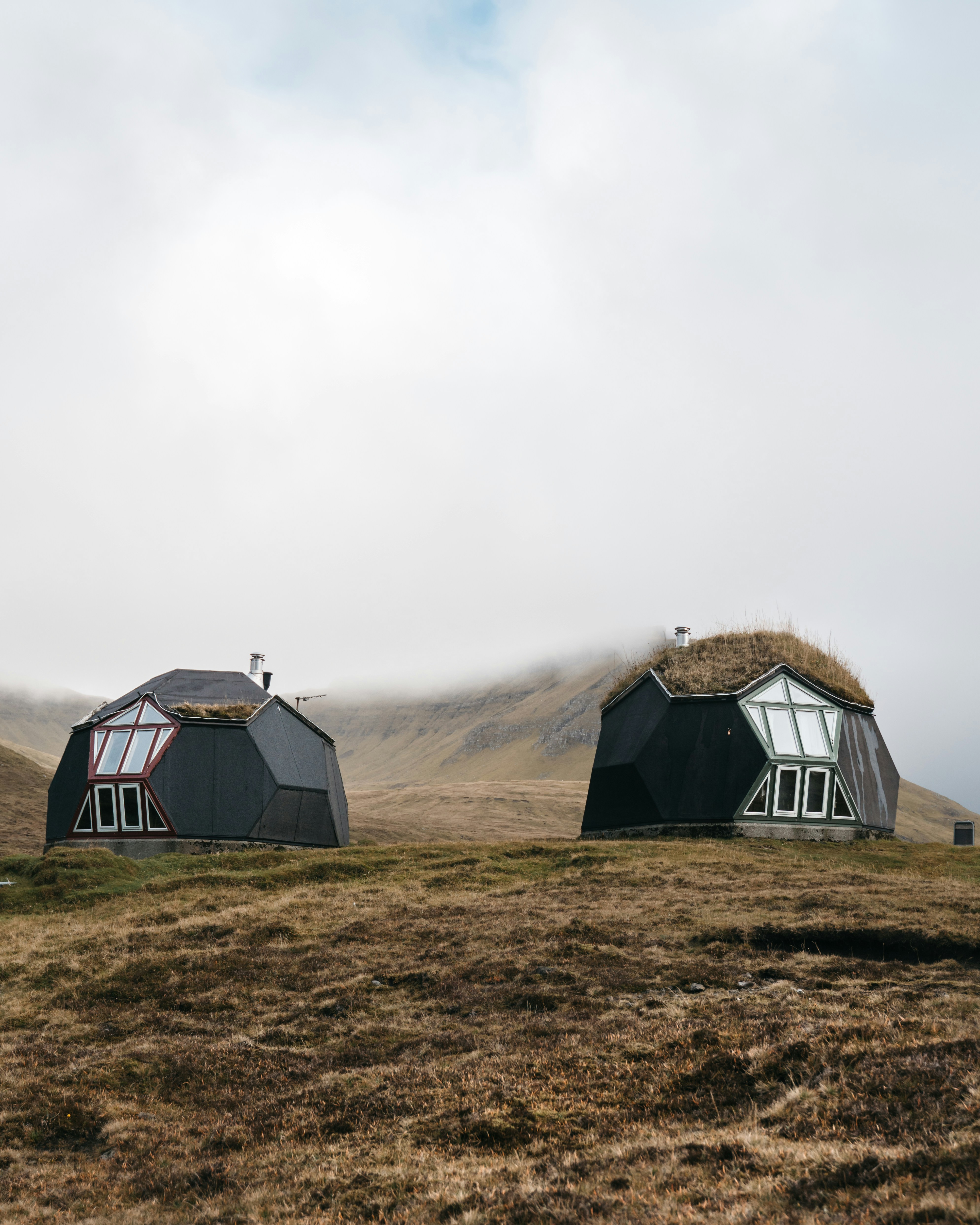 Grass-roofed cabins cling to a misty hillside
