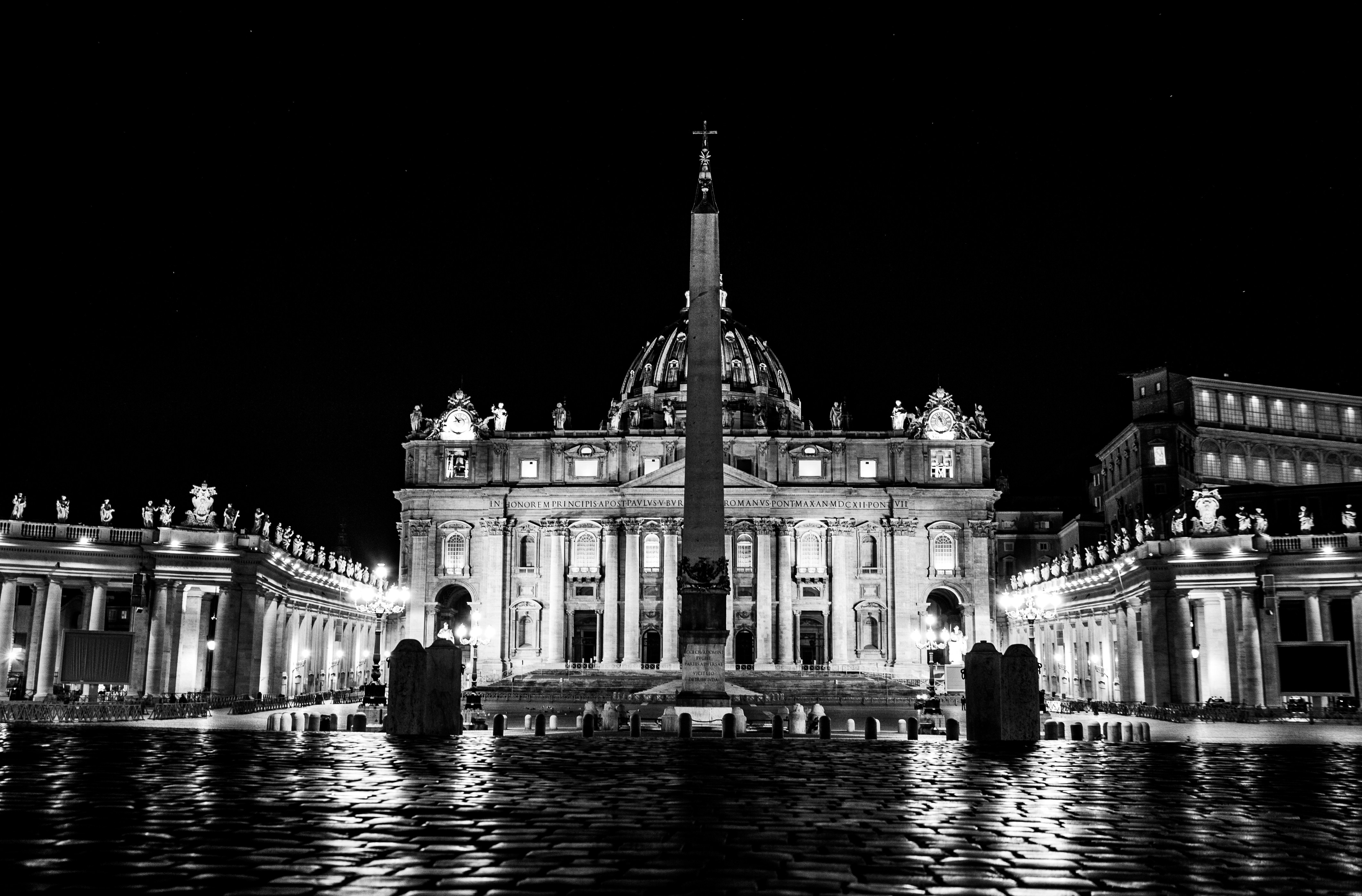 St. Peter's Basilica at night with its lights reflecting on the wet cobblestones.