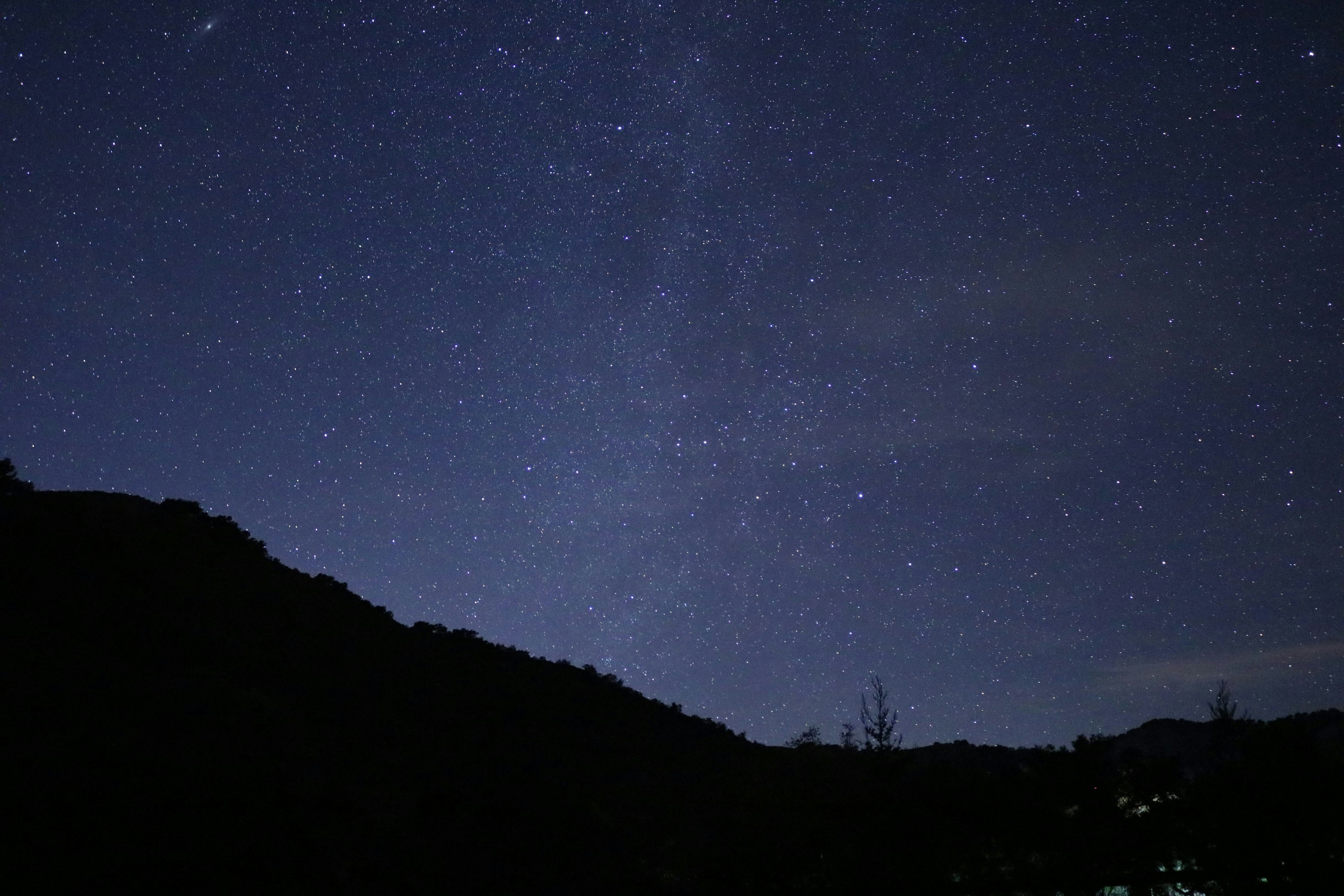 Silhouette of a mountain range under a vast, star-filled night sky.