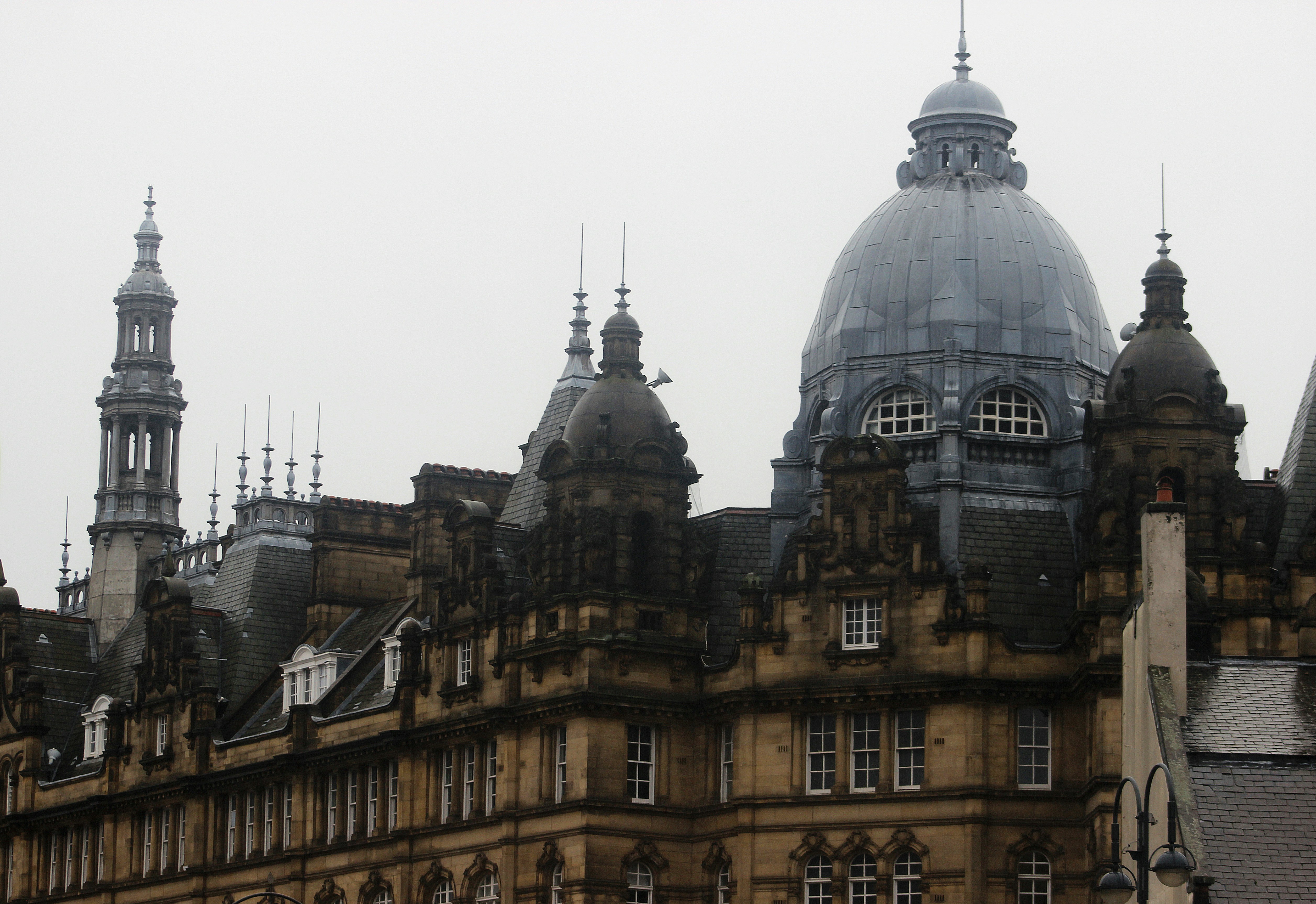 Ornate Gothic architecture with spires and domes against a gray, cloudy sky.