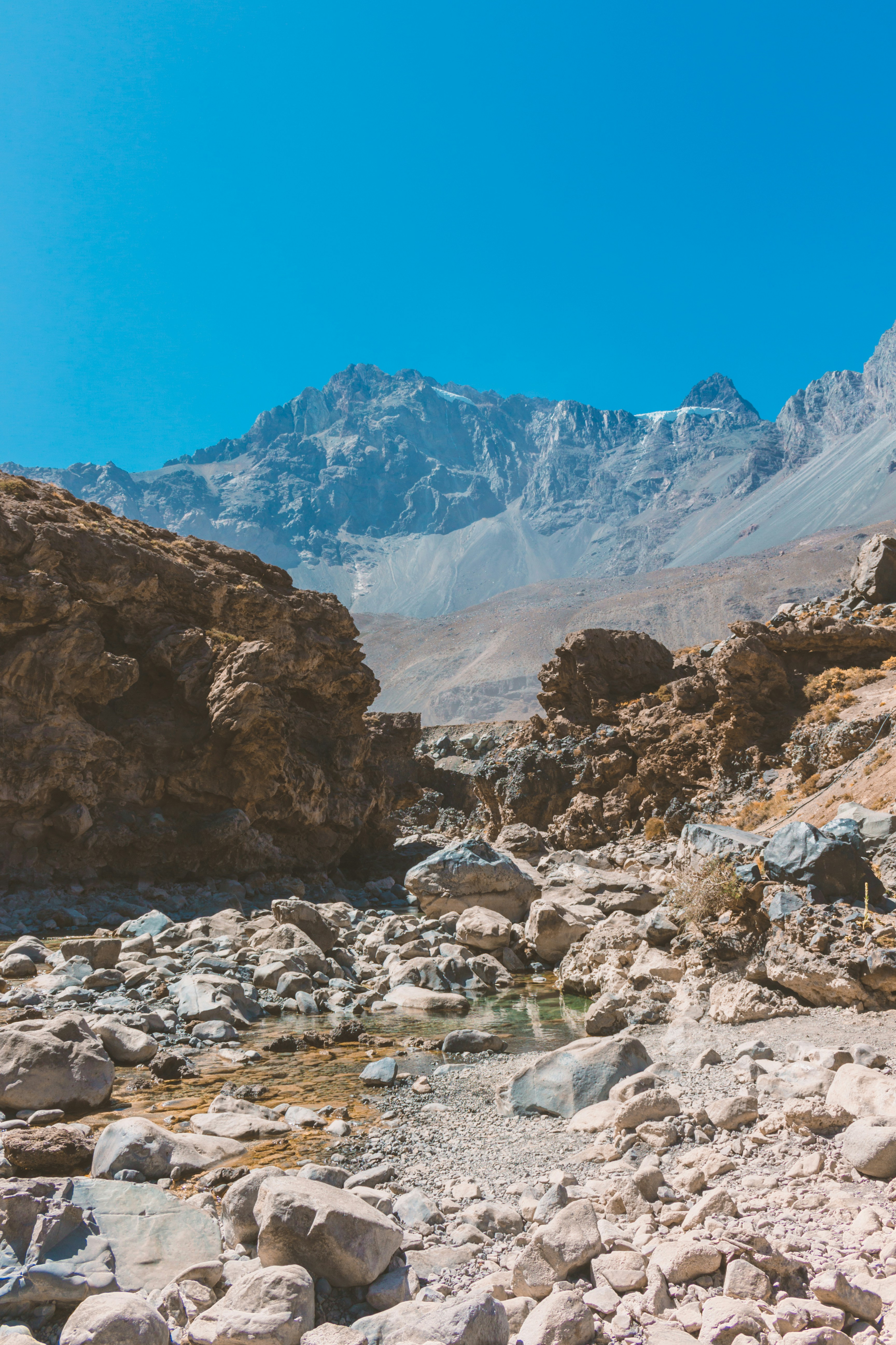 Rocky mountain landscape under a clear blue sky with a rugged path leading through the terrain.