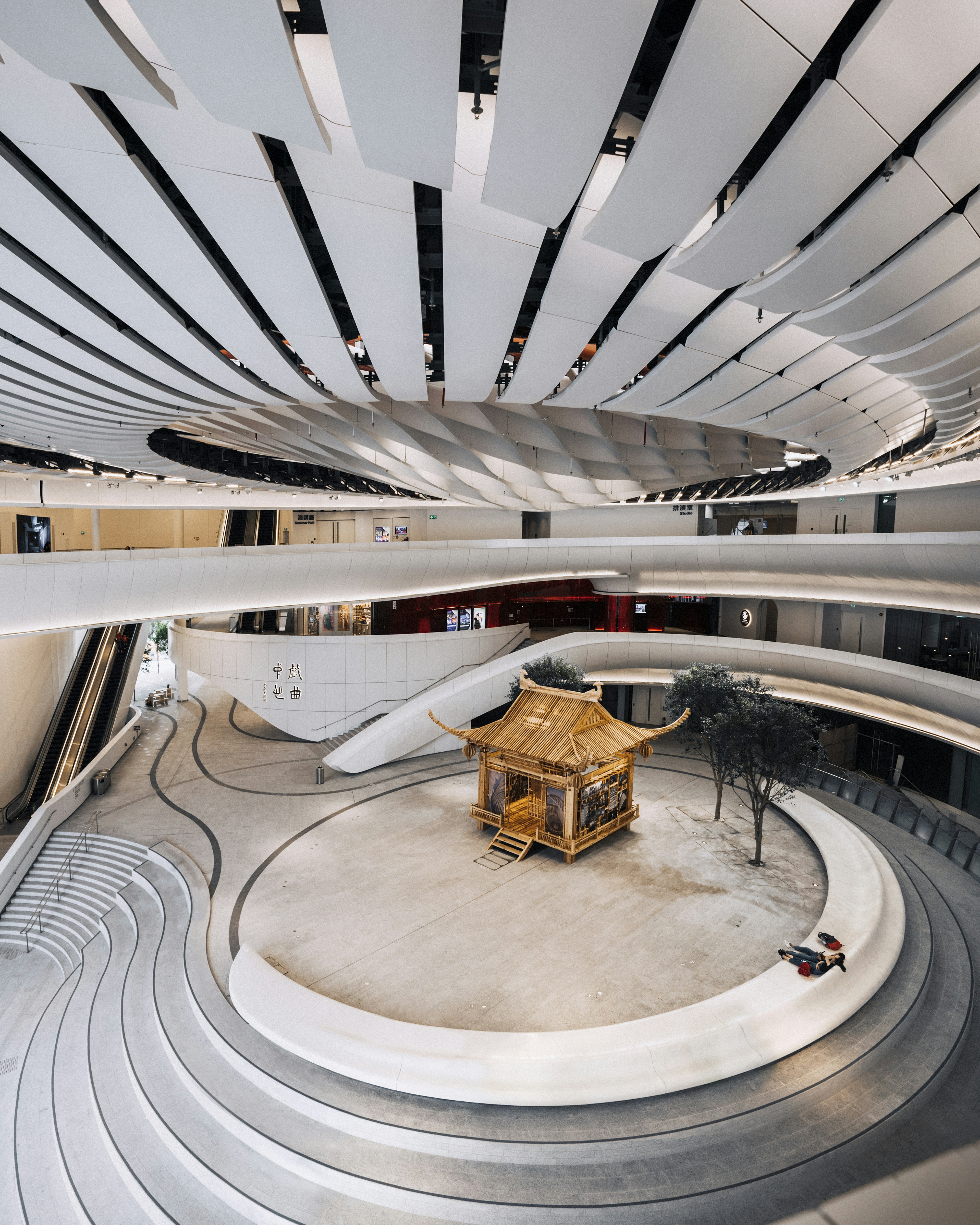 A minimalist interior featuring a traditional wooden pavilion surrounded by sweeping white architectural lines and gentle curves. The serene atmosphere invites contemplation.