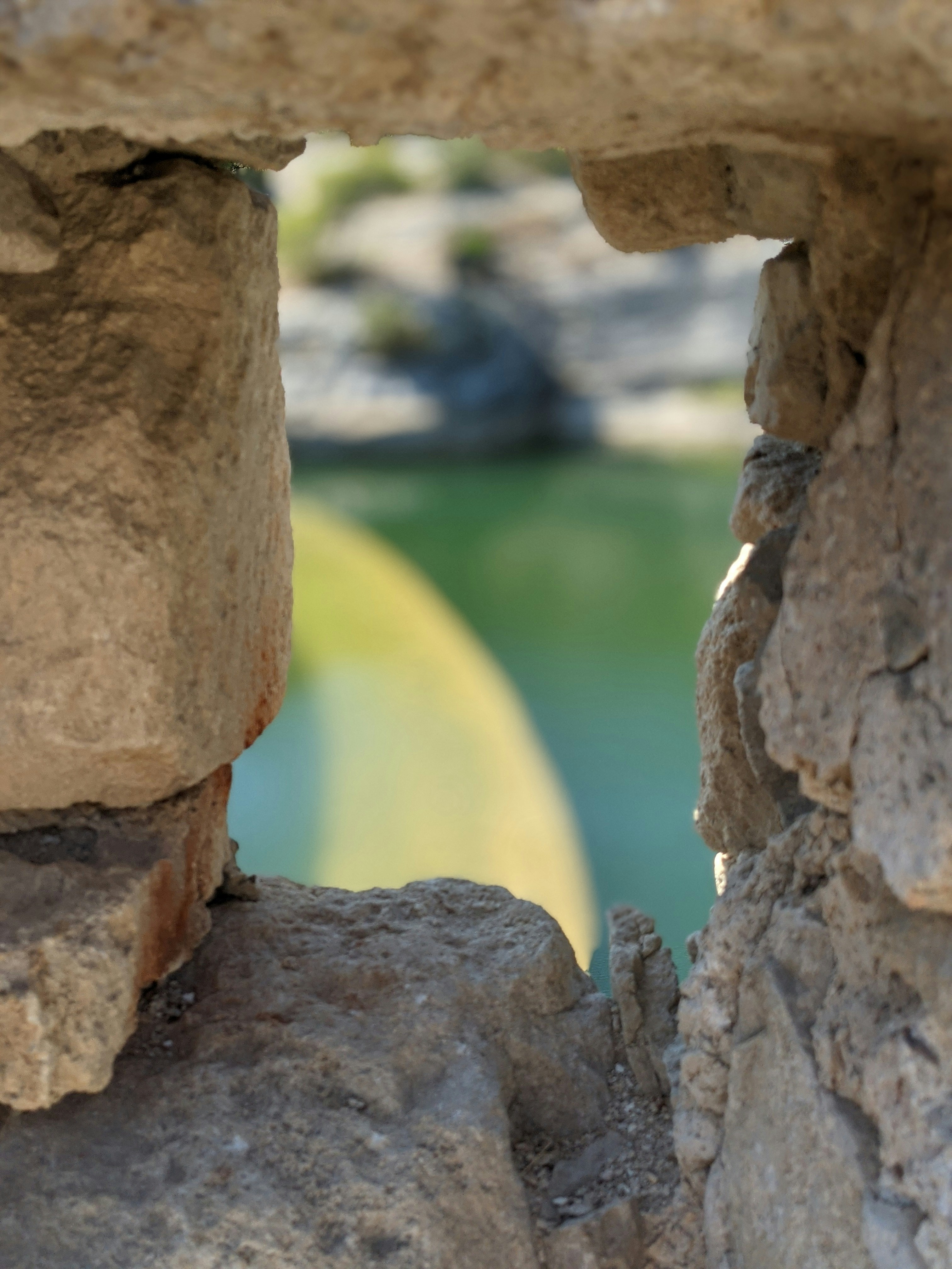 Through a Pebbled Frame: A Quiet View Beyond Crumbling Walls