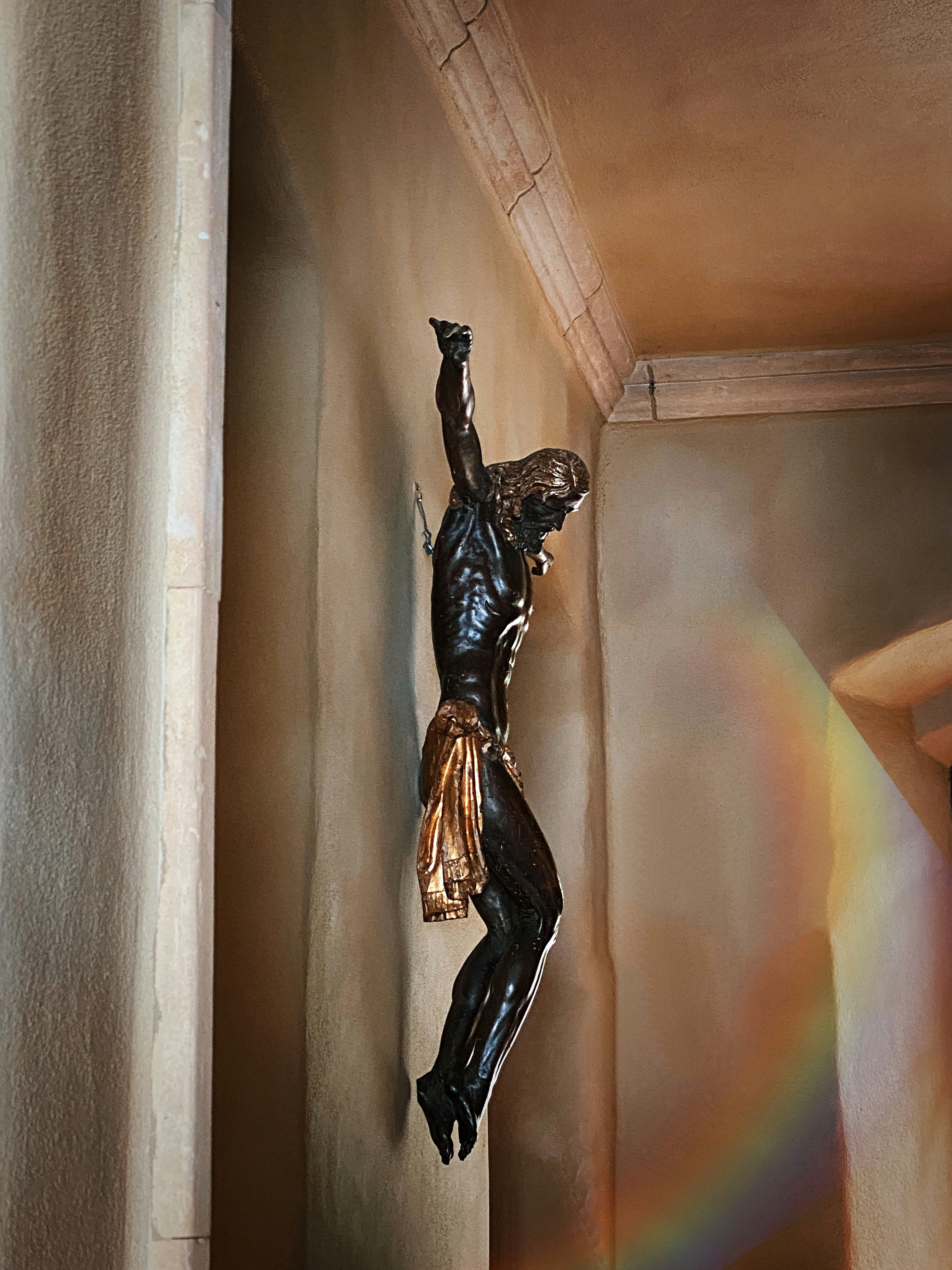 Bronze Crucifix in Warm Glow with a Rainbow Prism