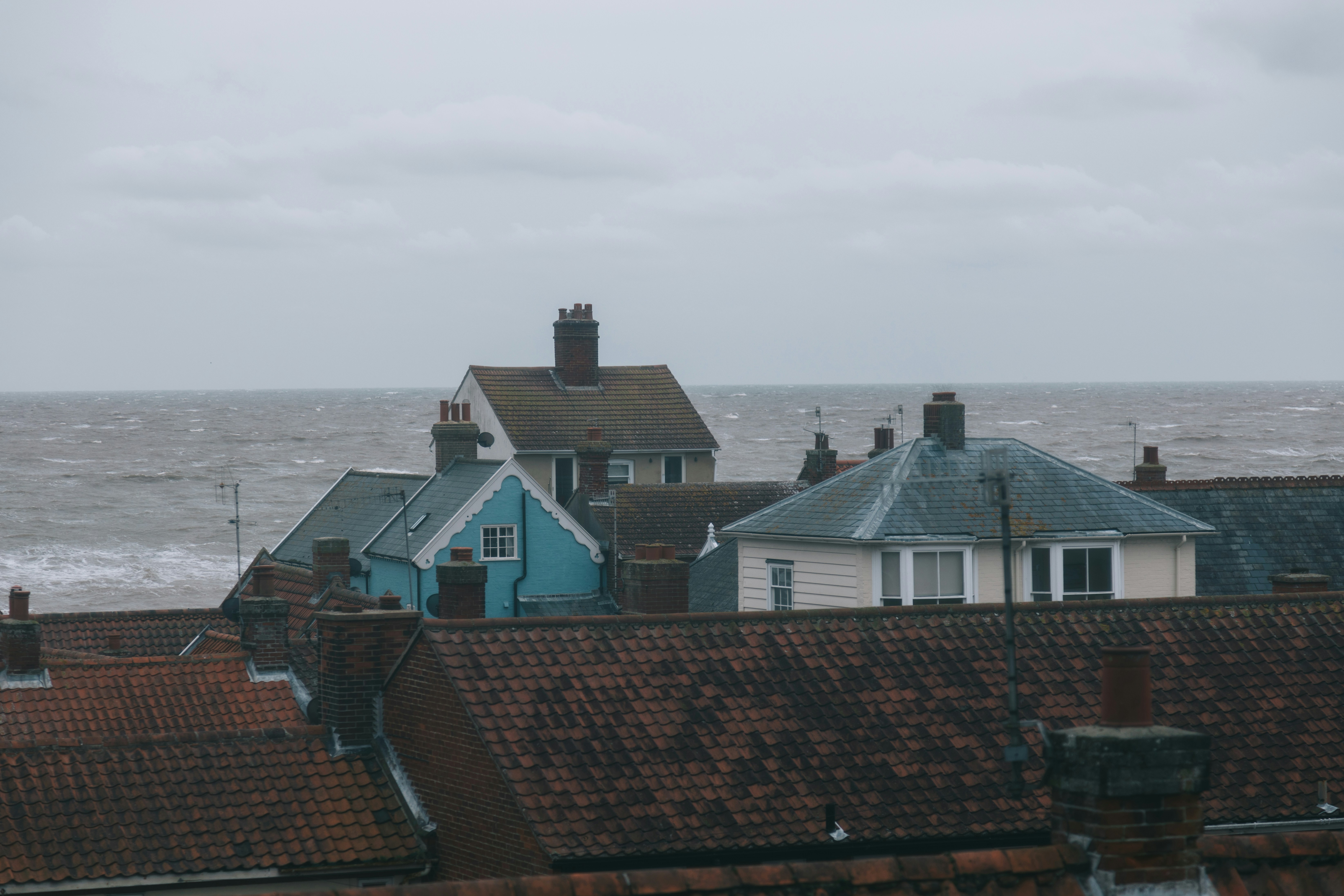 Teal House on a Rooftop Row Against a Distant Sea