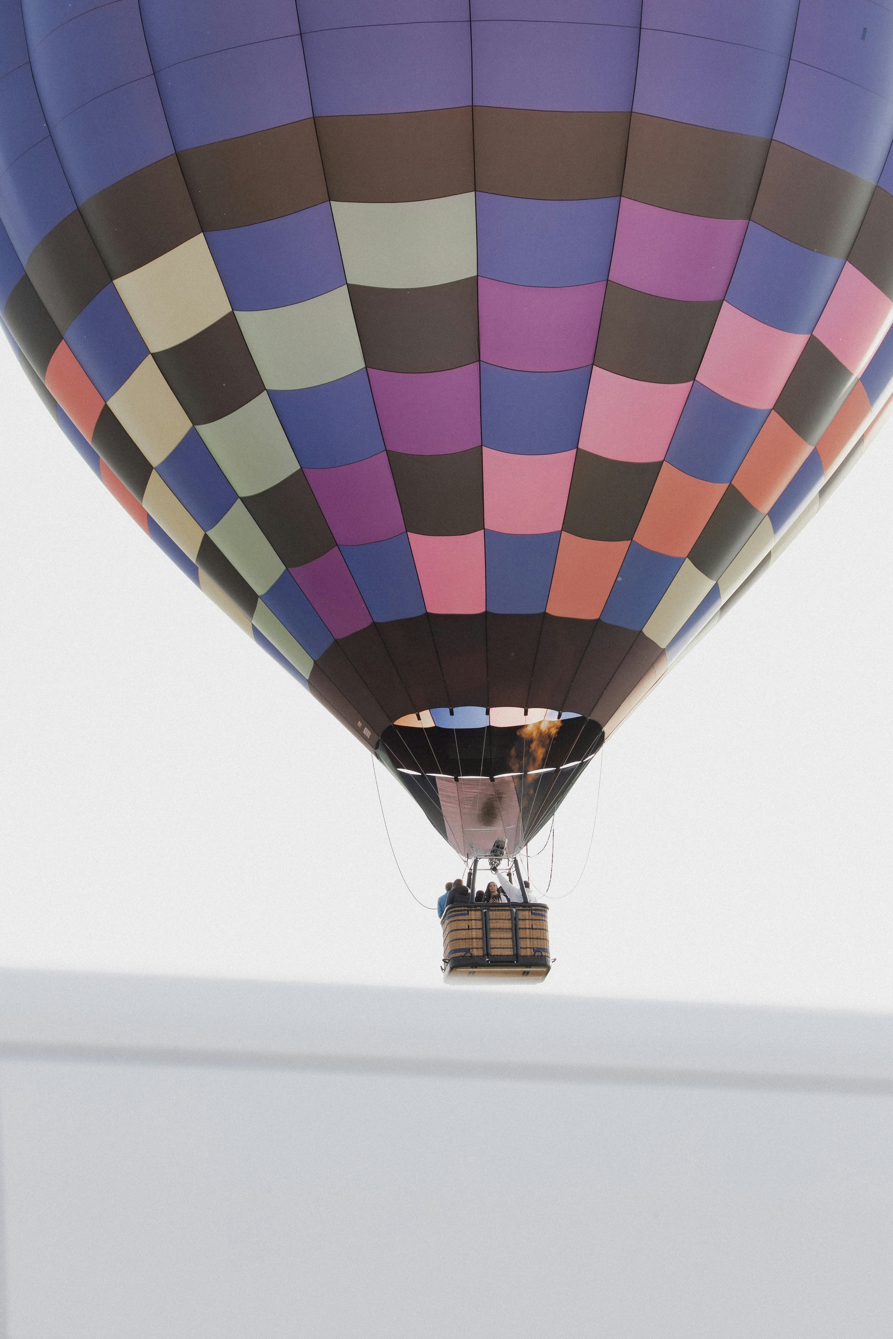 Elevated ascent: Colorful hot air balloon lifting off against a pale horizon