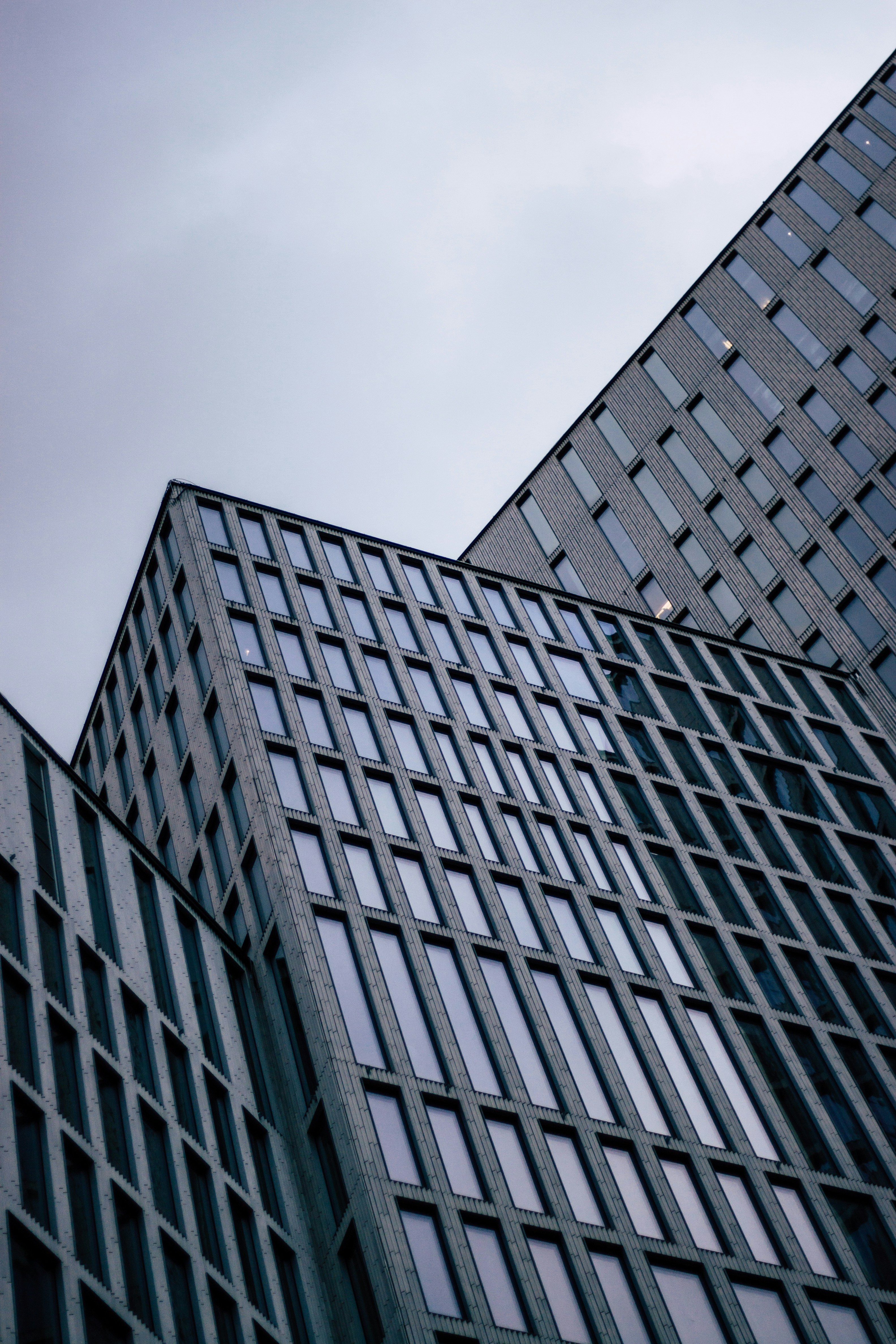 Angular skyscrapers reflect a moody sky, showcasing modern architectural design and geometric patterns.
