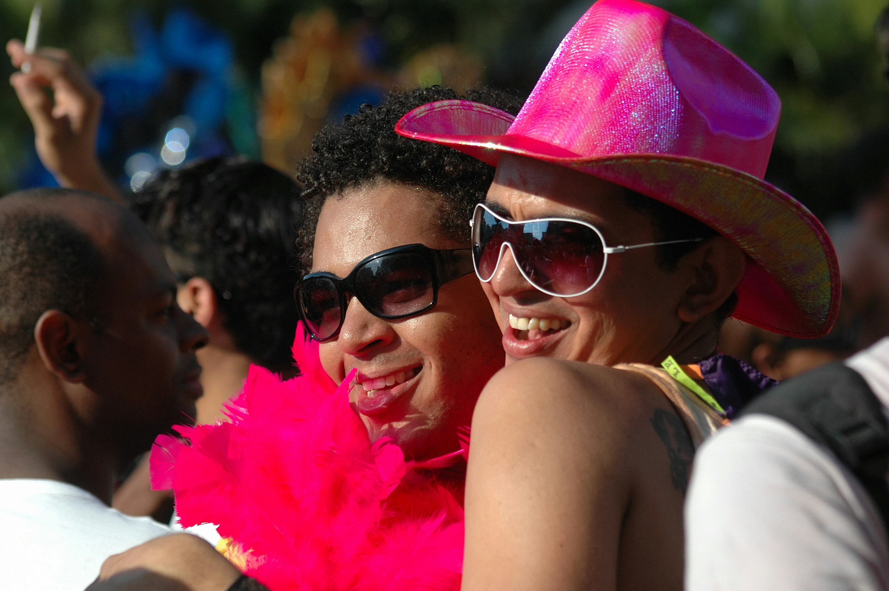 Two joyful revelers share a sunny moment at a street festival