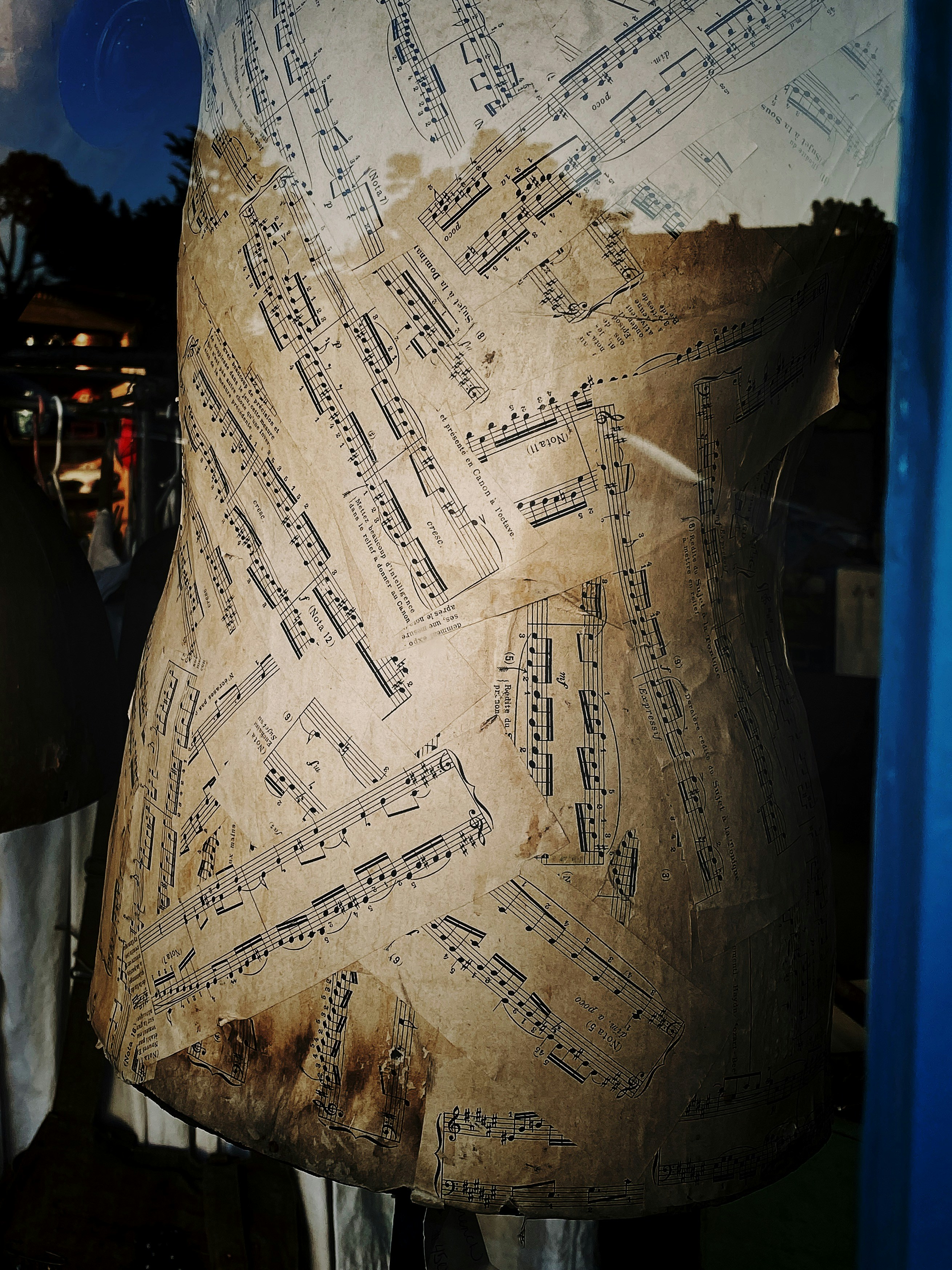 Score-Wrapped Silhouette: A Life-Size Sculpture Cloaked in Weathered Sheet Music.