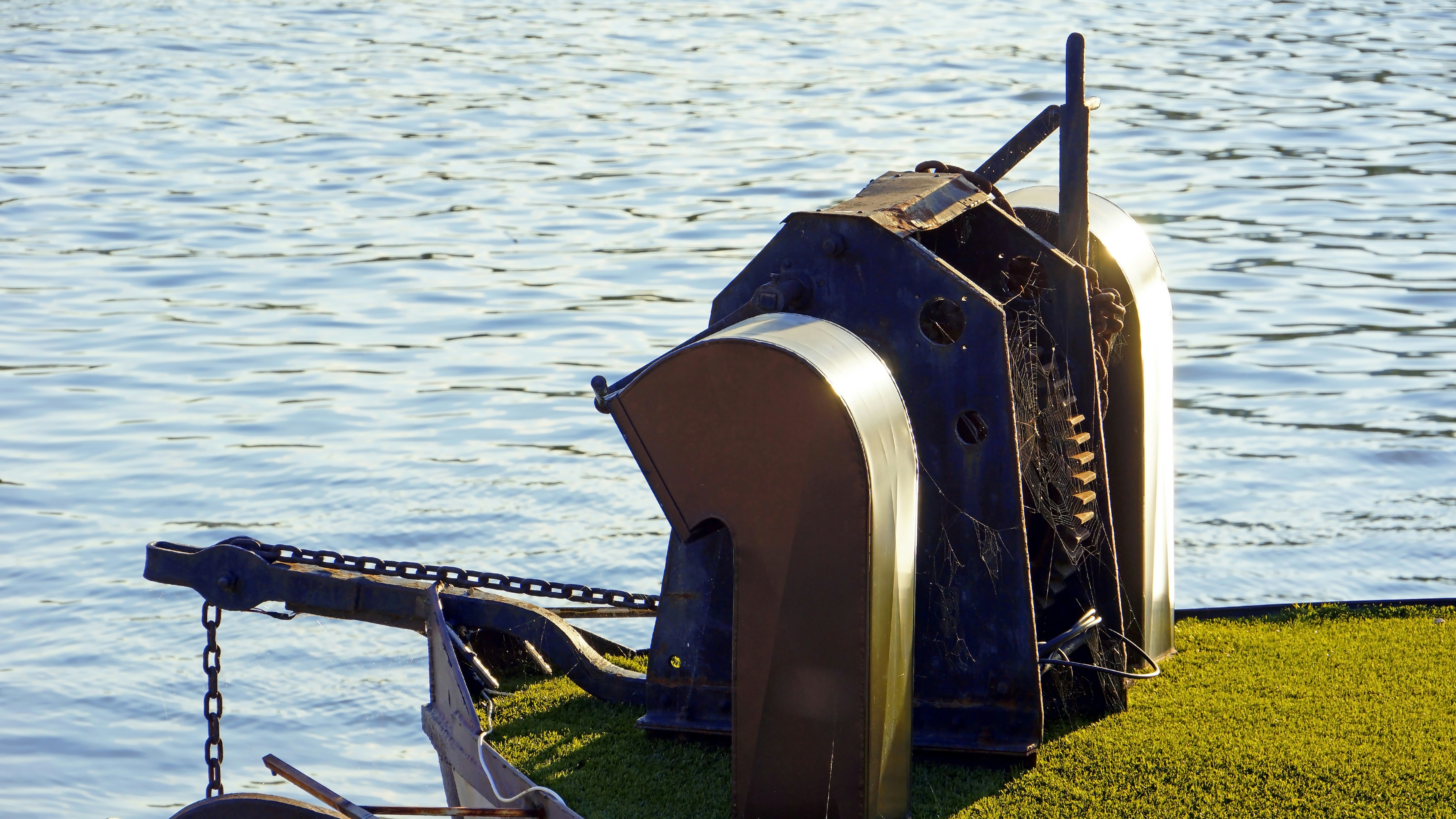 black and brown metal equipment on green grass near body of water during daytime
