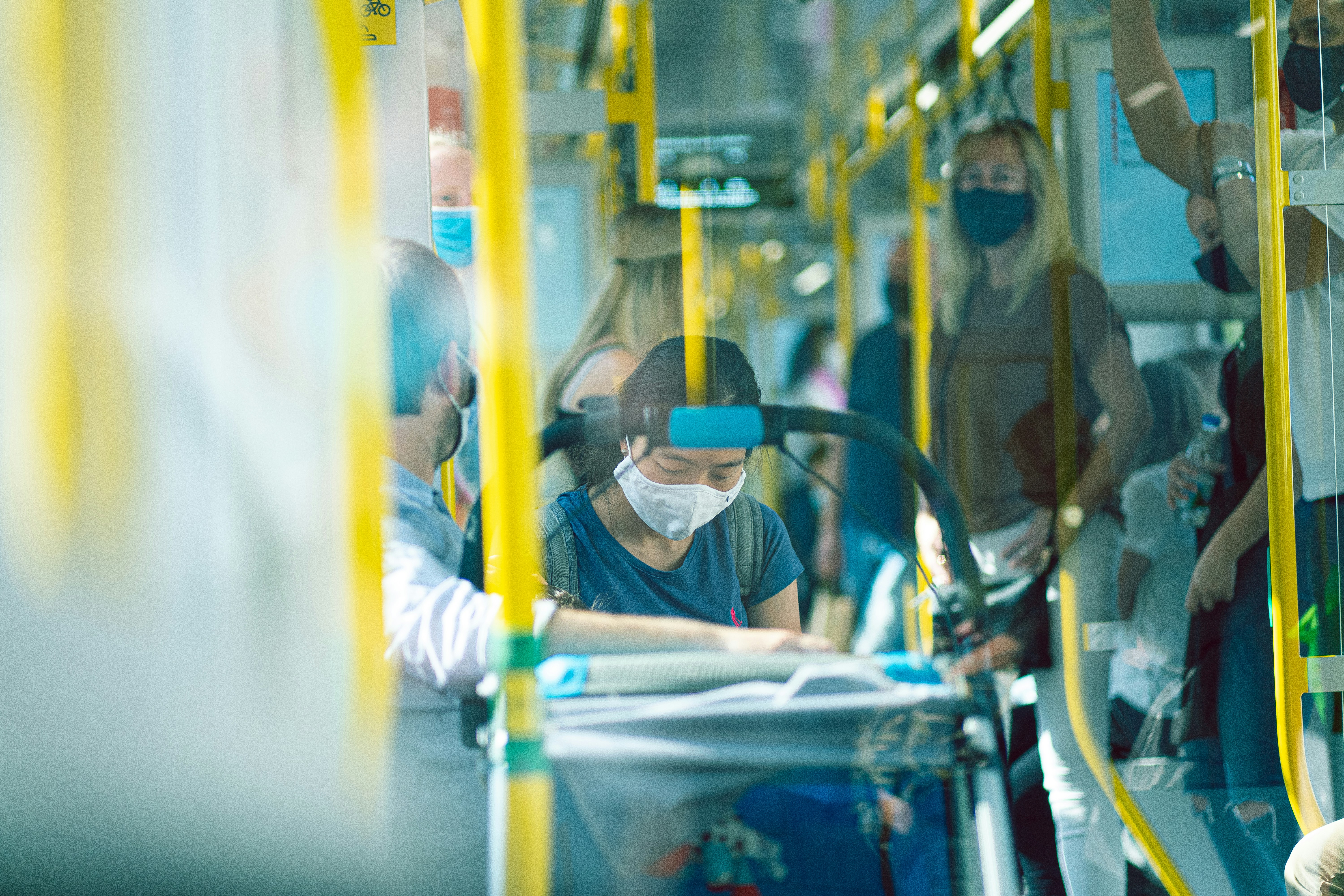 Focused Masked Commuter Amid a Crowded Bus Aisle