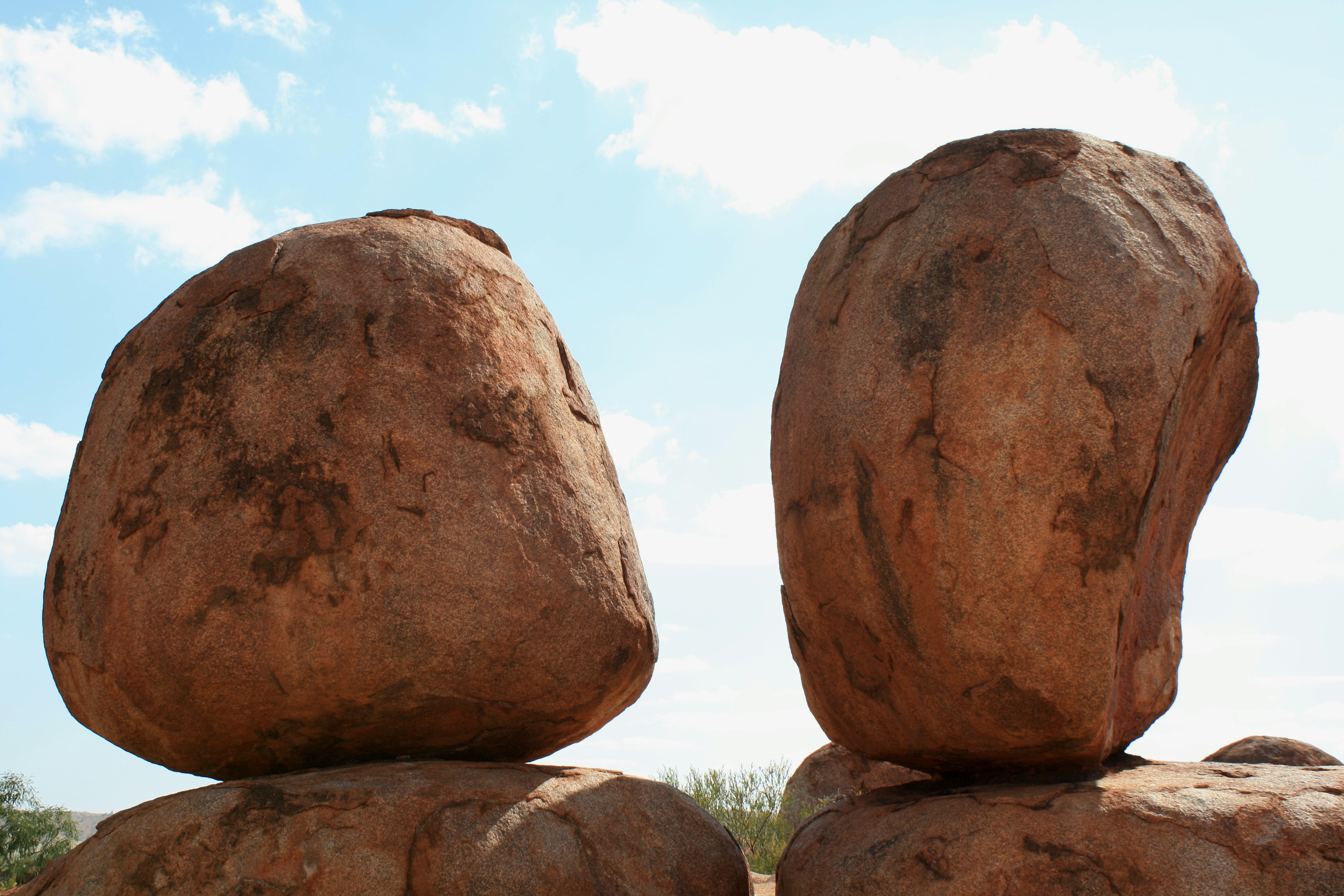 Massive boulders balanced atop smaller rocks under a bright blue sky.