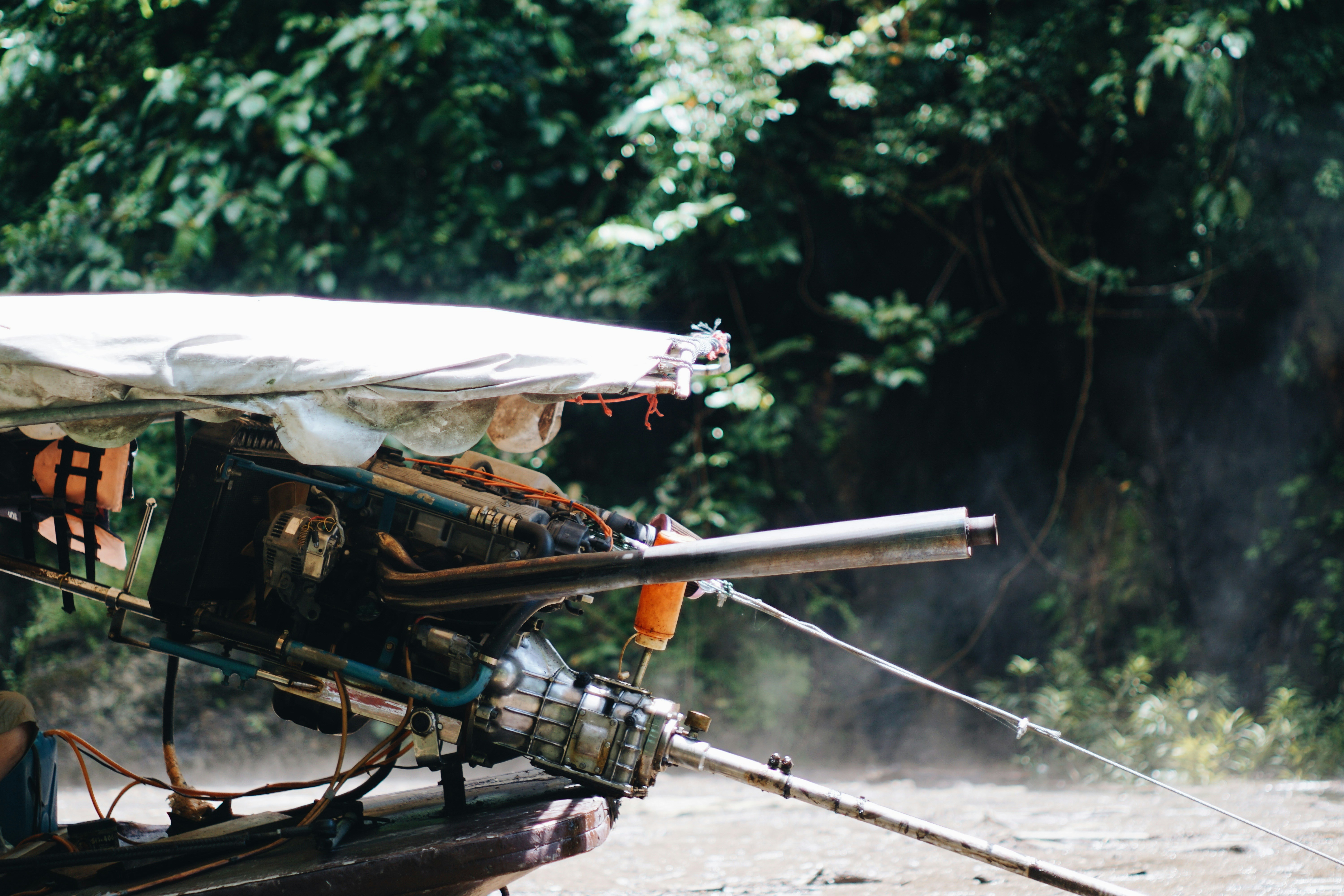 Close-up of a boat's engine mounted on a wooden frame, surrounded by lush greenery. The scene captures the essence of river navigation in a natural setting.