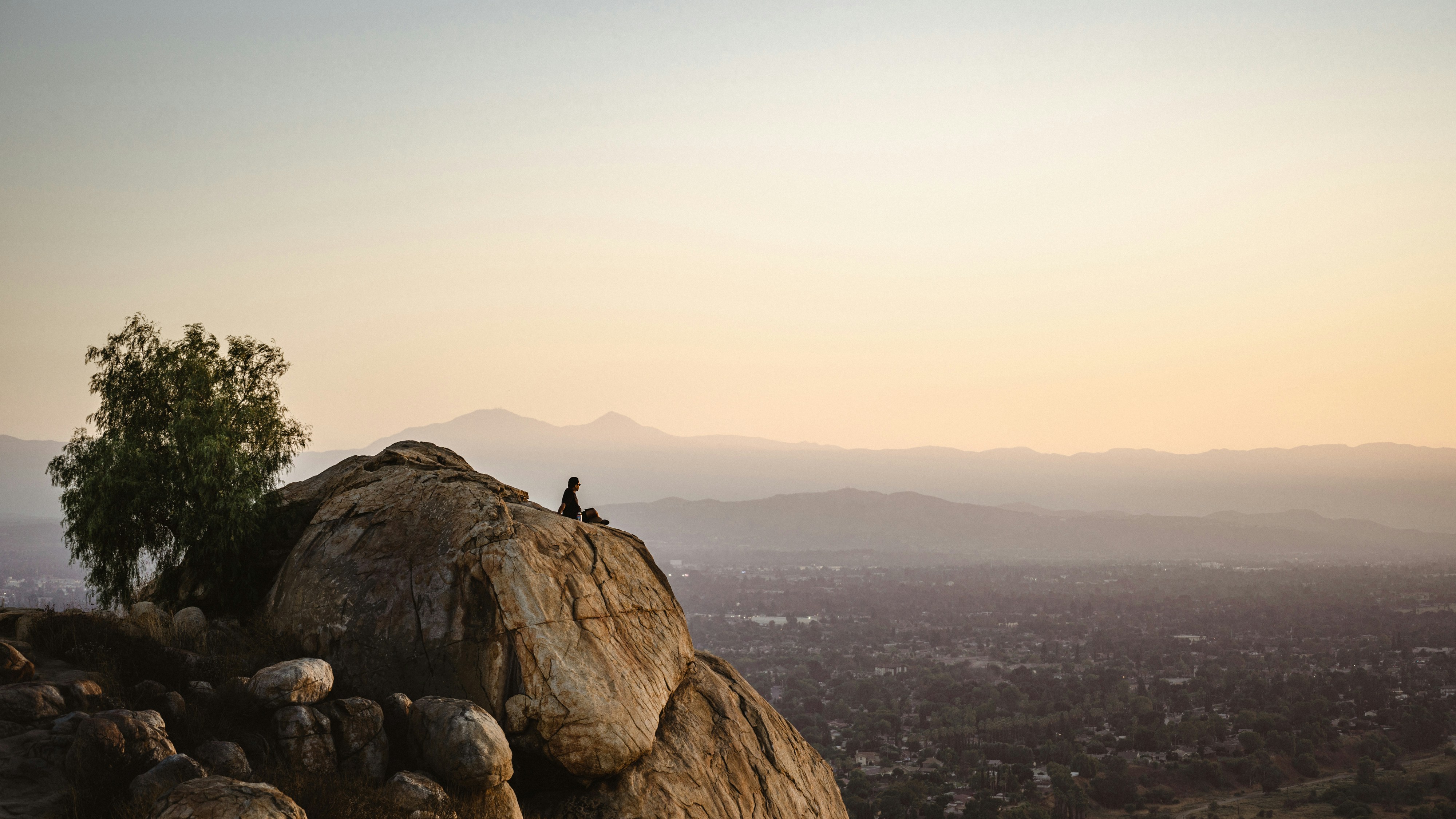 looking out onto riverside on top of mount rubidoux | person standing on rock formation near body of water during daytime