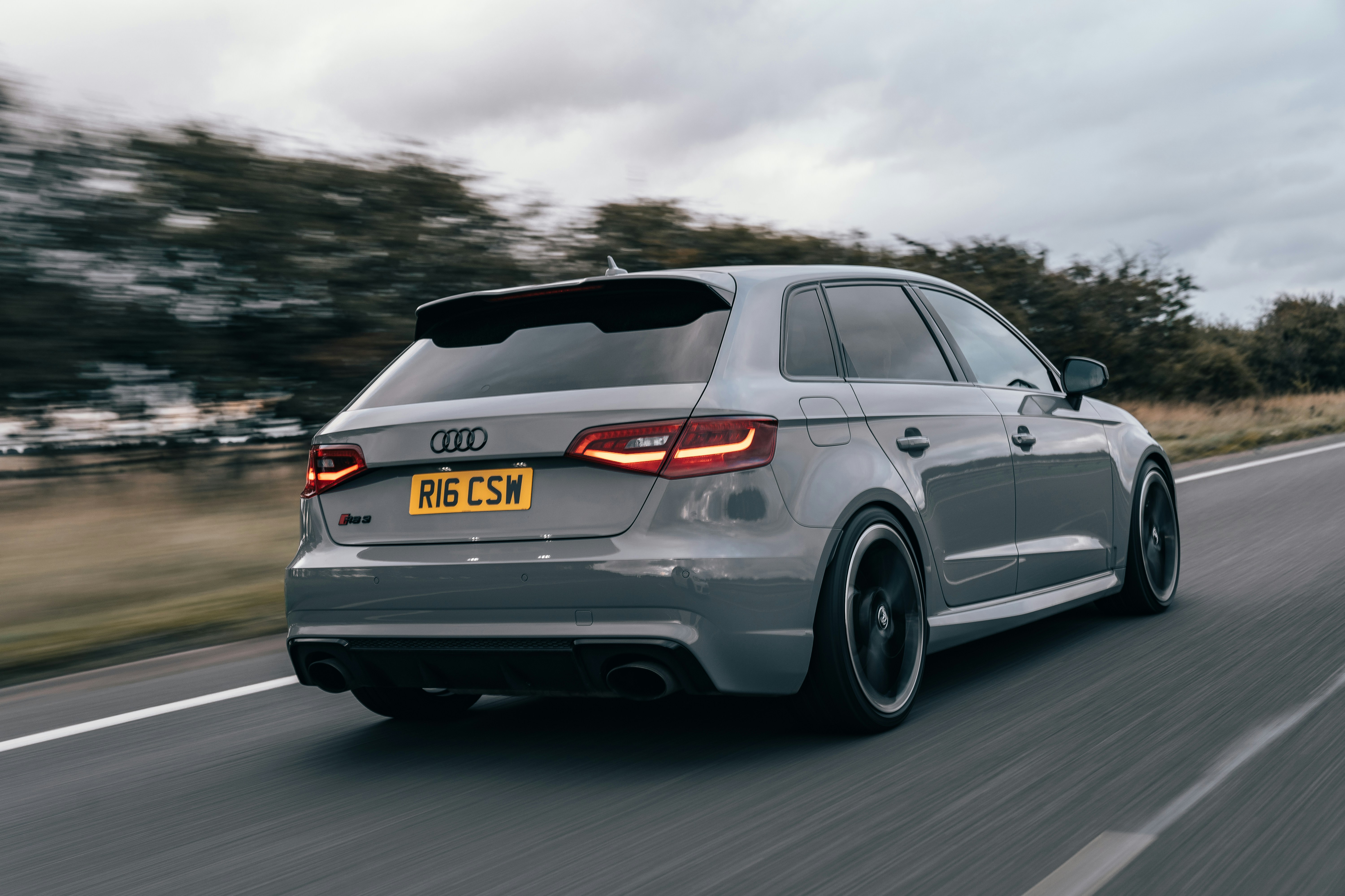 Audi A3 speeding down a winding road, showcasing its sleek design and performance capabilities.