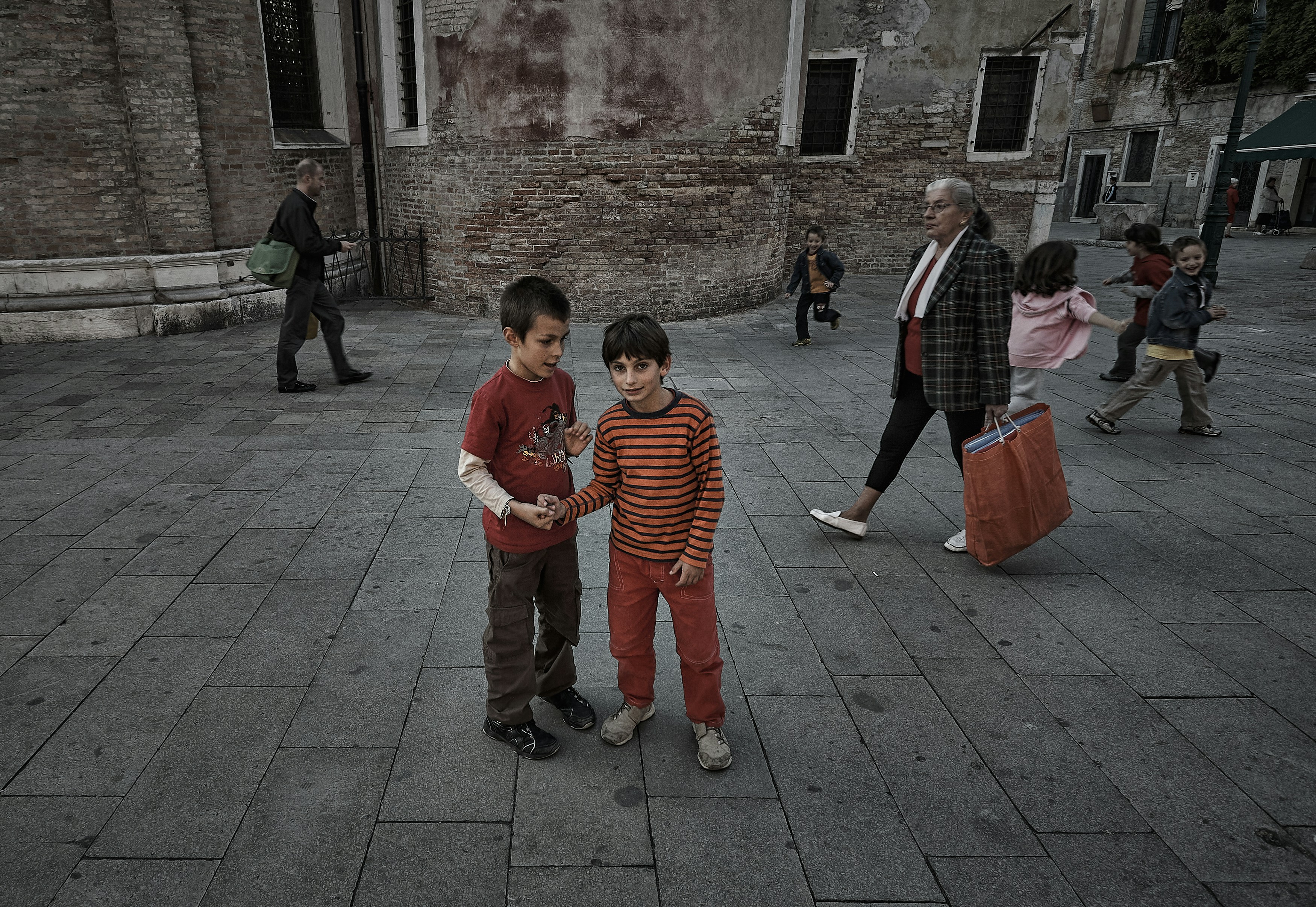Two Red-Shirt Boys Share a Quiet Moment in a Weathered City Square