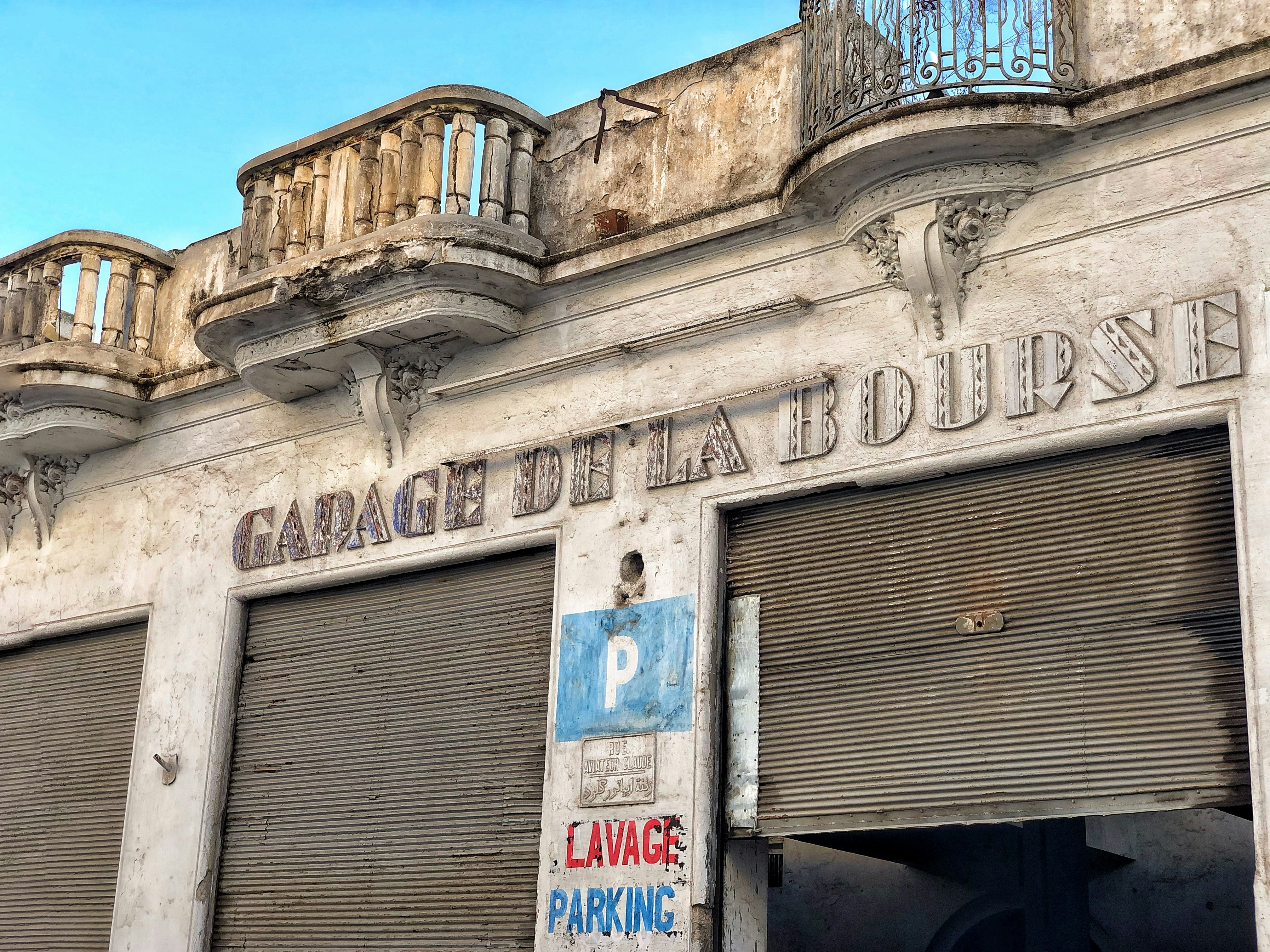 A weathered vintage garage in Casablanca with faded signage and architectural details under a clear blue sky.