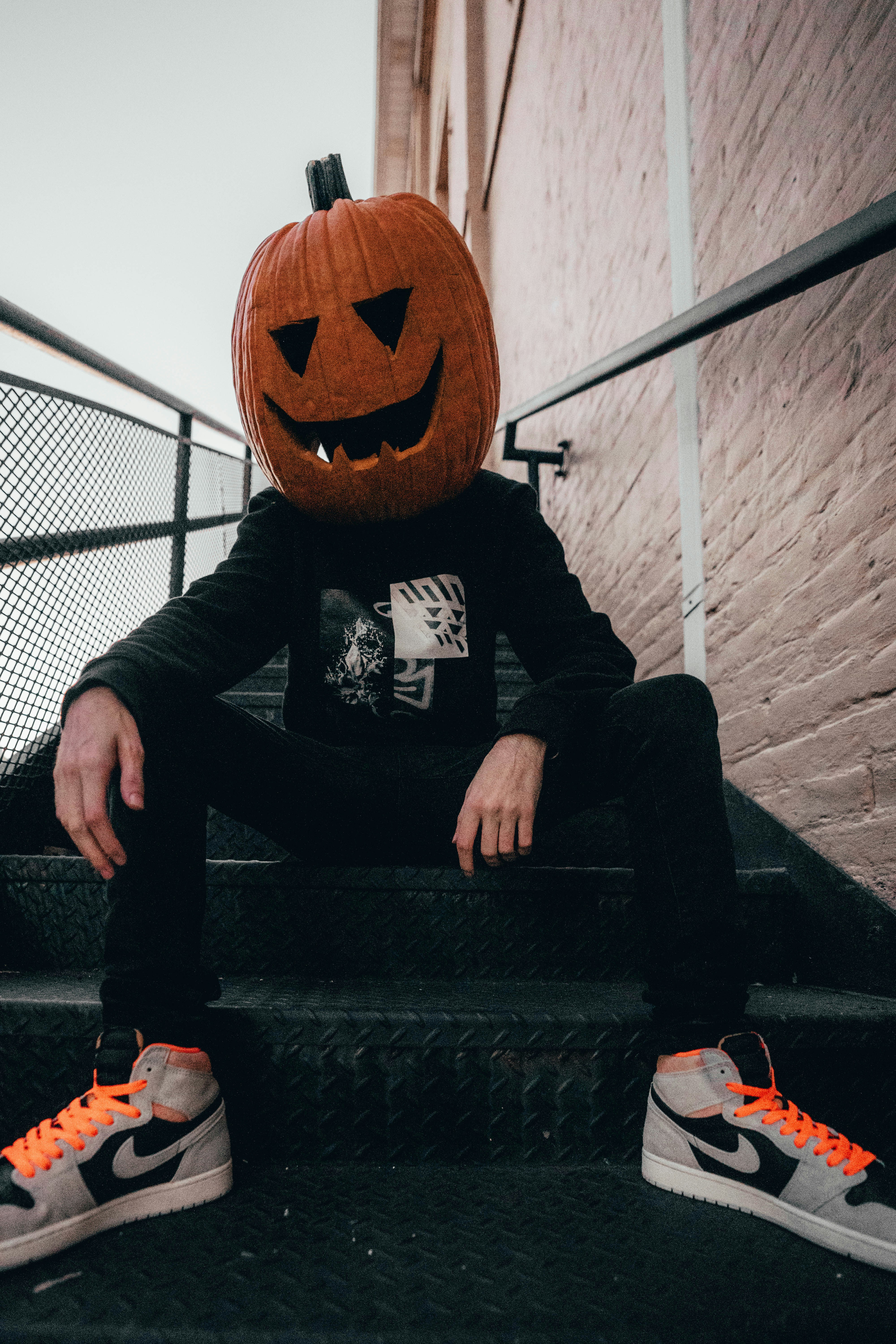 a person sitting on steps with a pumpkin on their head