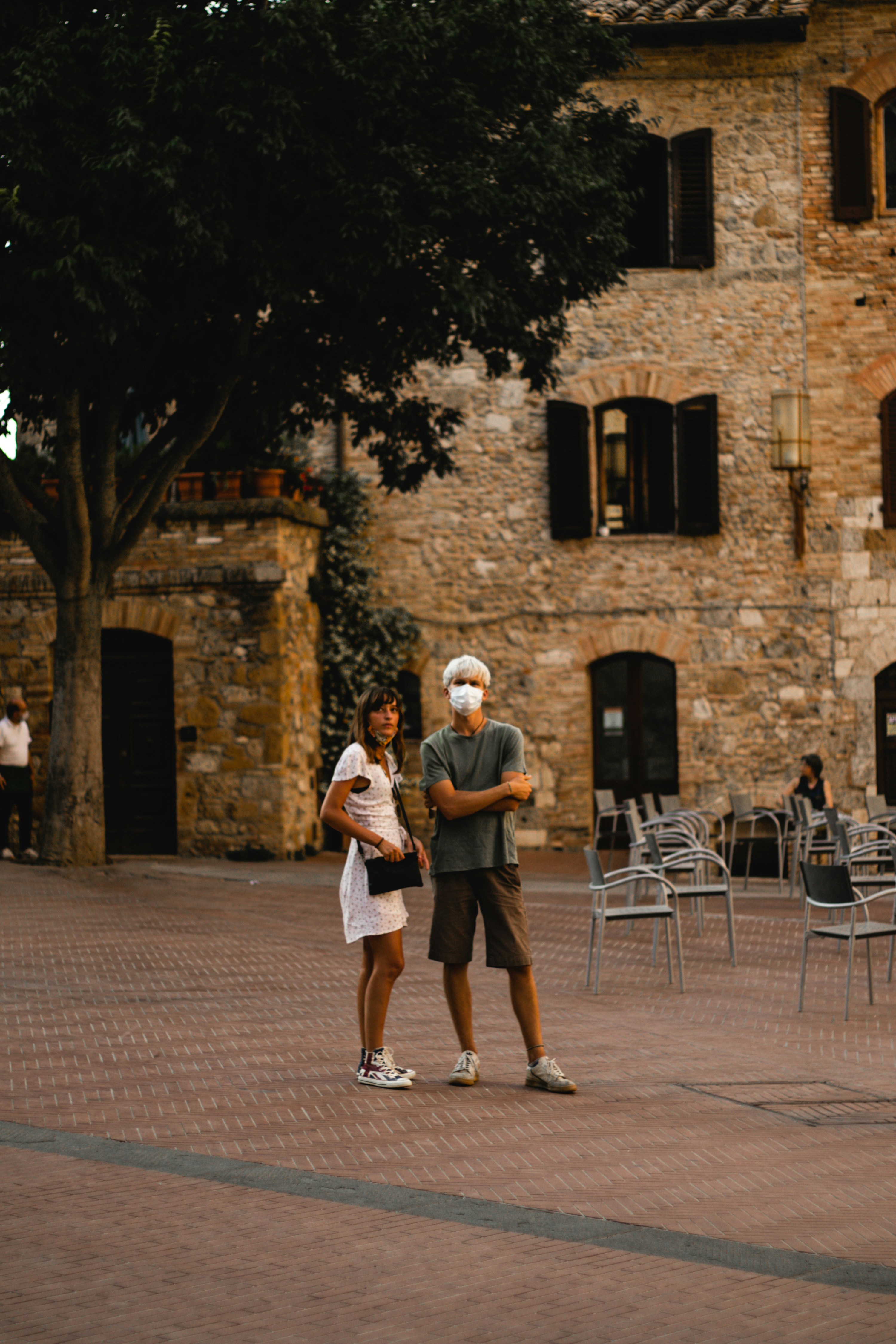Mask and Moment: Two Tourists in a Tuscan Courtyard
