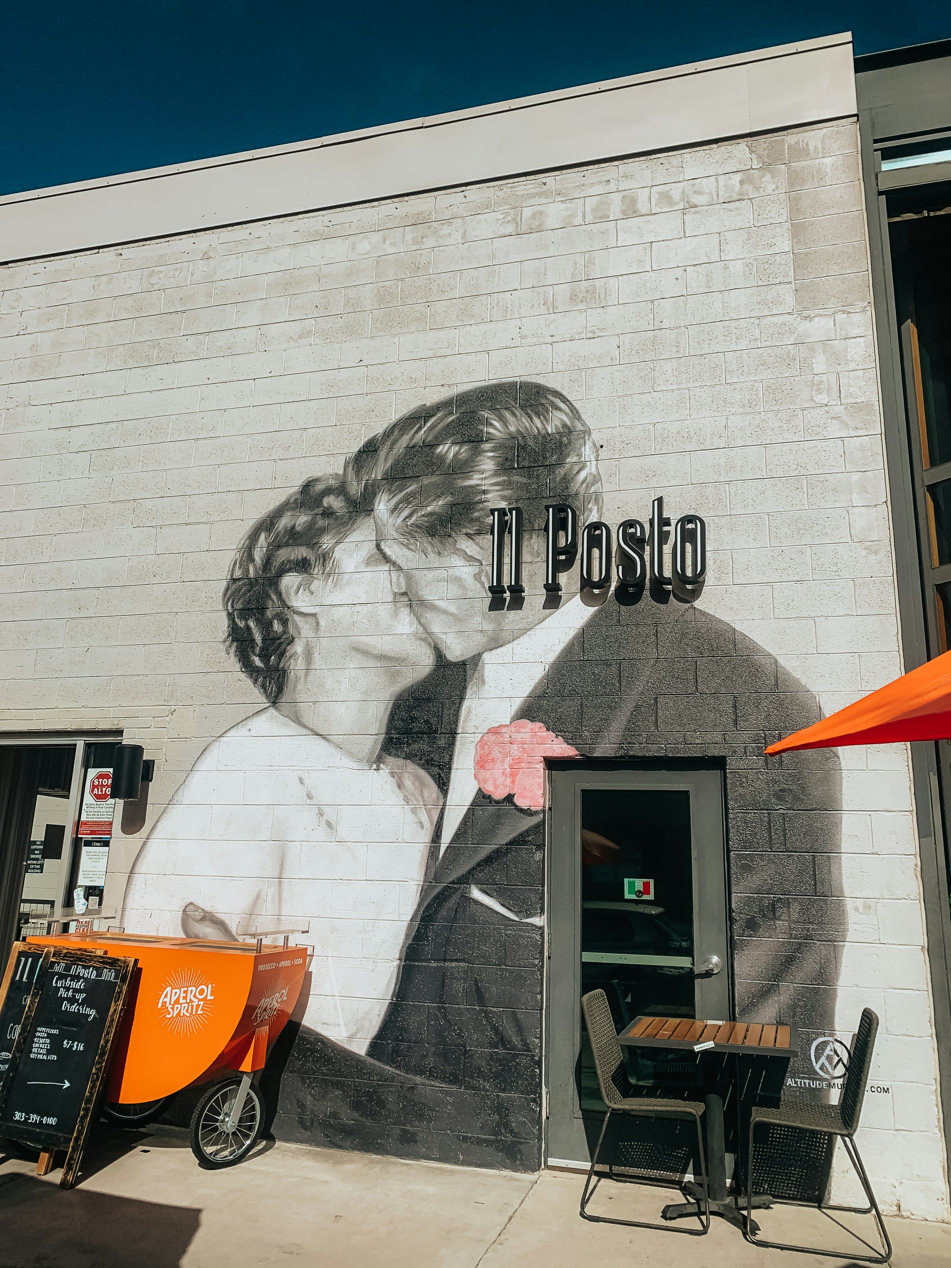 Kiss in front of a mural: Il Posto wall portrait at street cafe