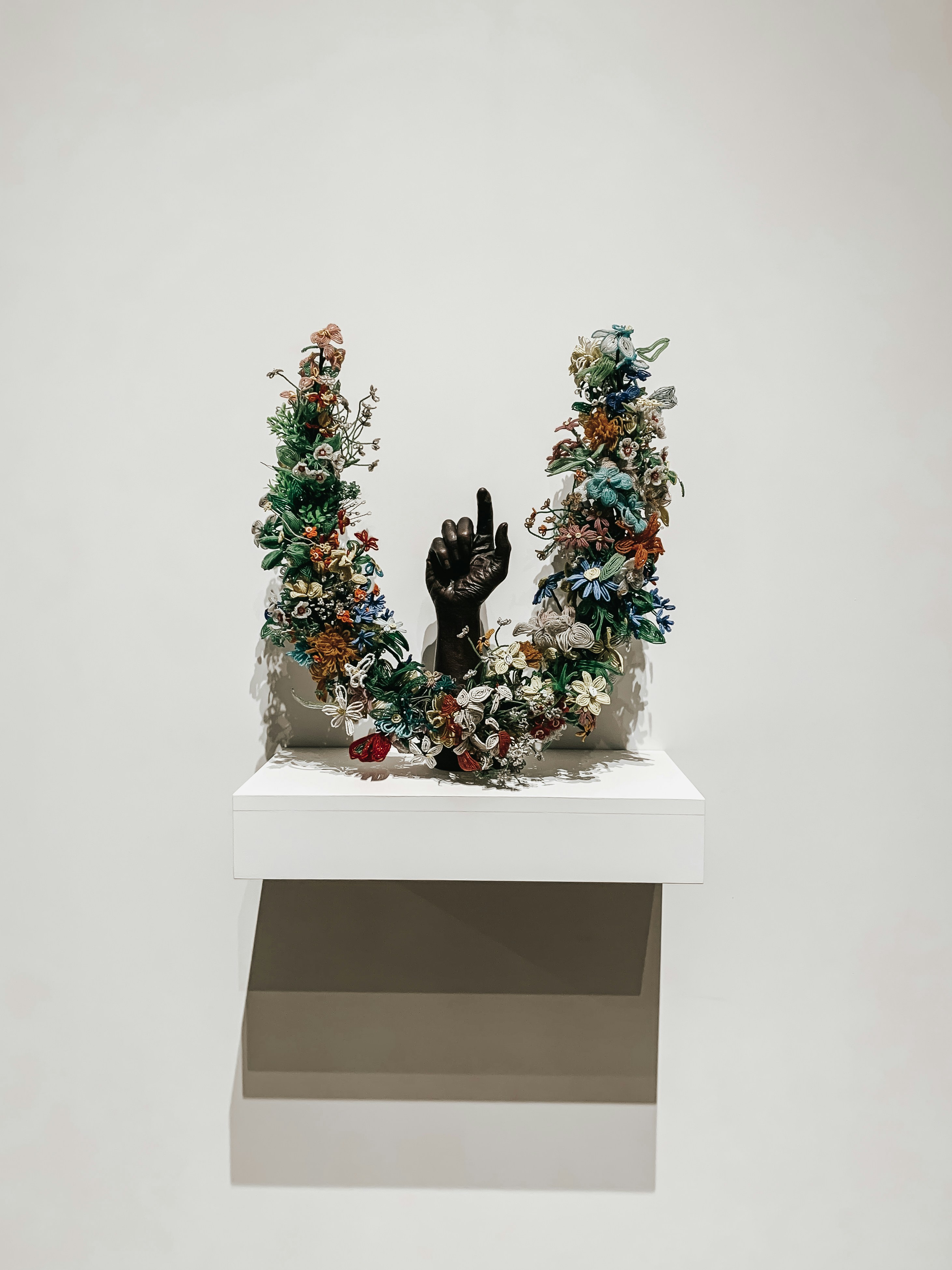 Floral V-Gesture: A Black Hand Rising From a Garden Wreath