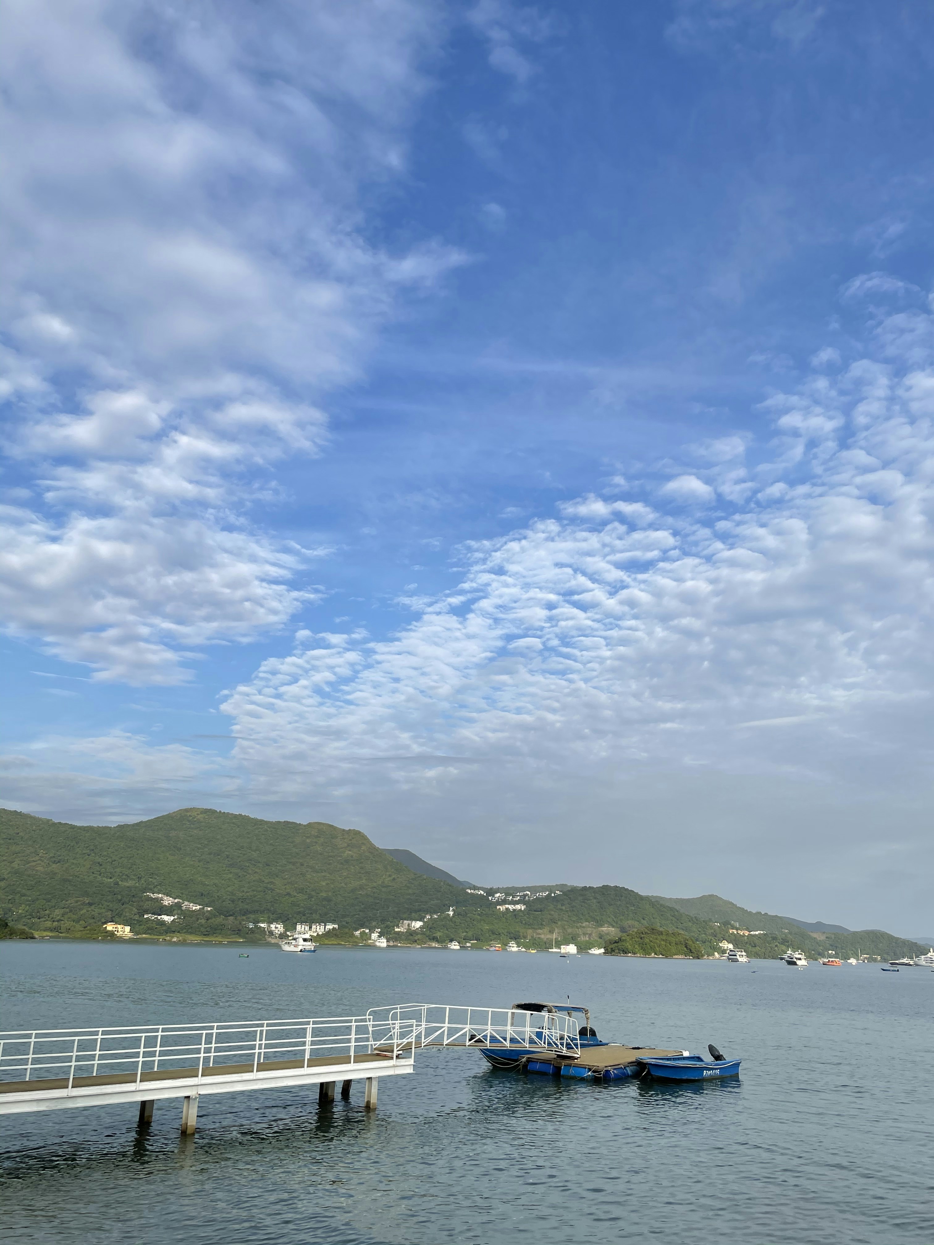 Harbor Quiet: White Pier, Blue Boats, and a Sky Laced with Clouds