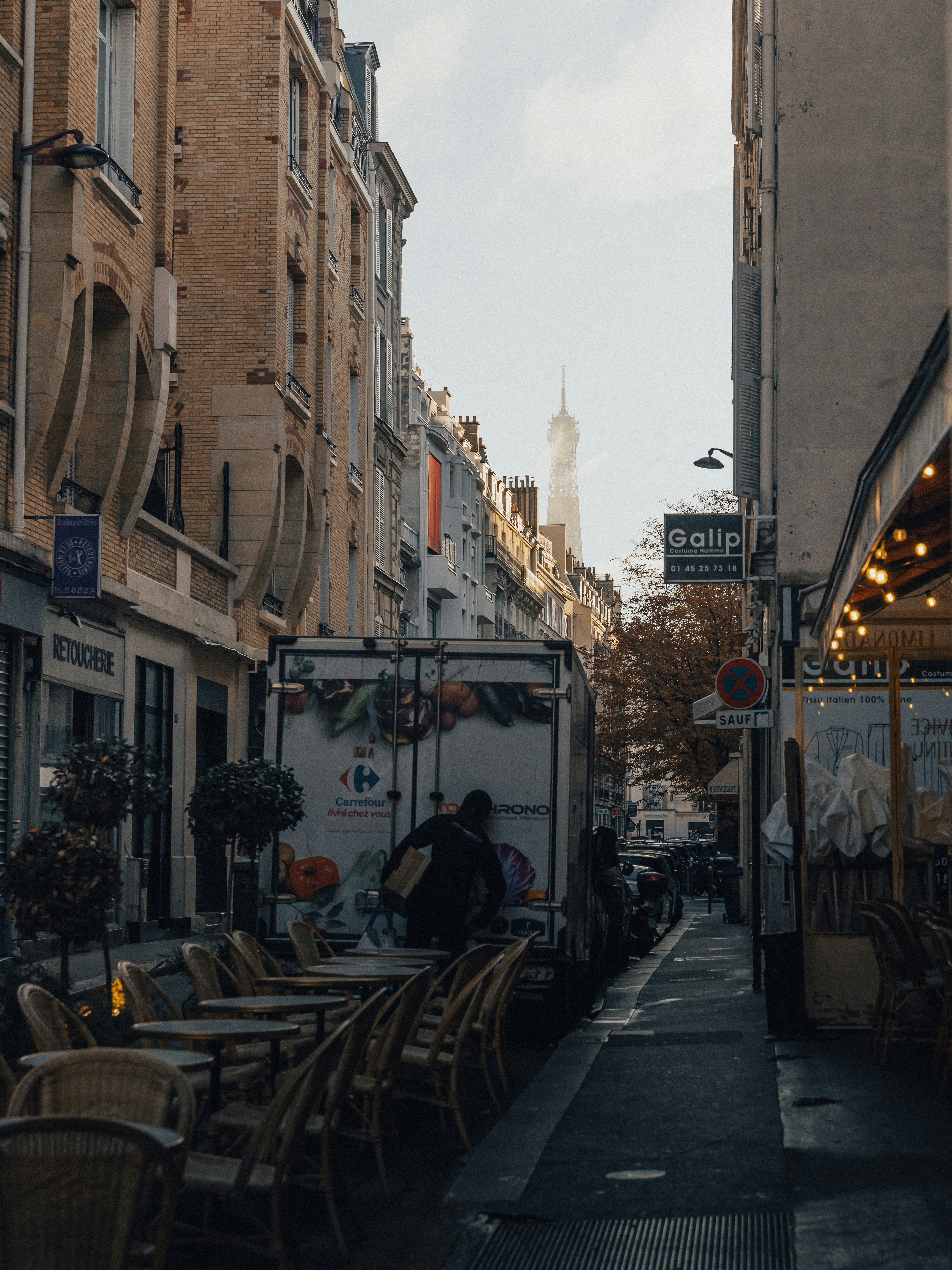 Copper-Lit Boulevard: Café Tables, Facades, and a Distant Tower