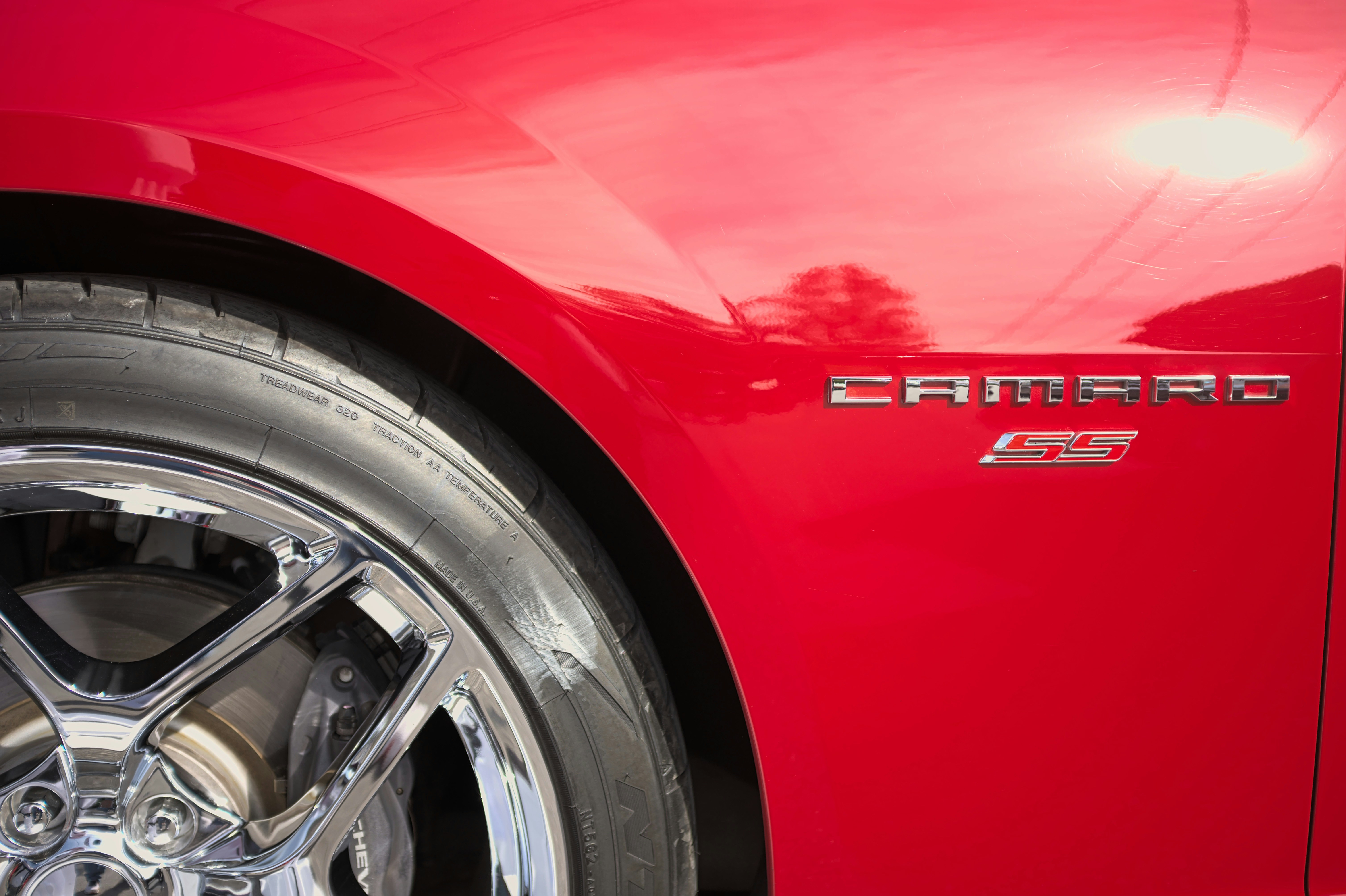 Scarlet Chrome: A Close-Up on the Camaro Badge and Rim