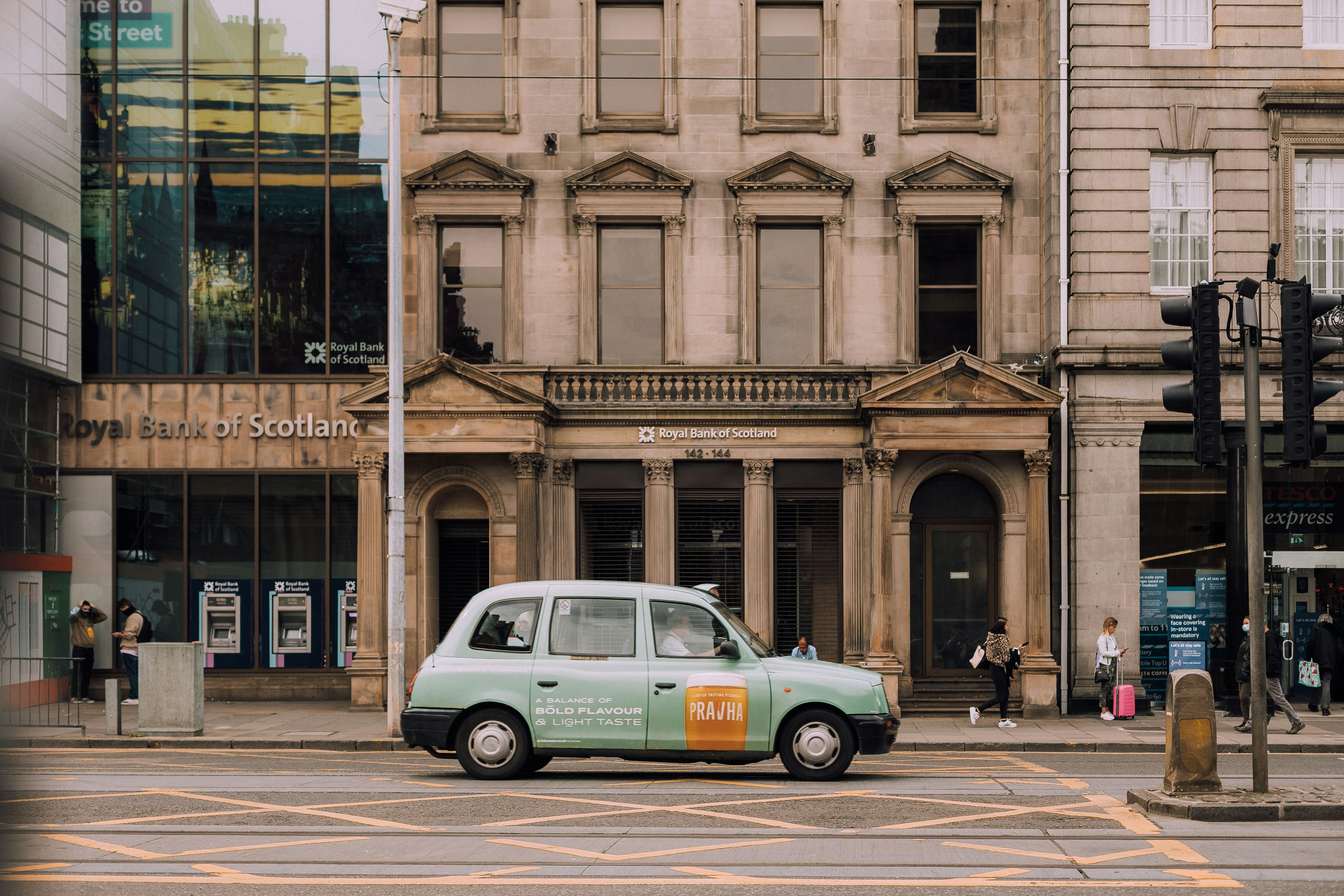 Classic green taxi at a city intersection with historic architecture backdrop.