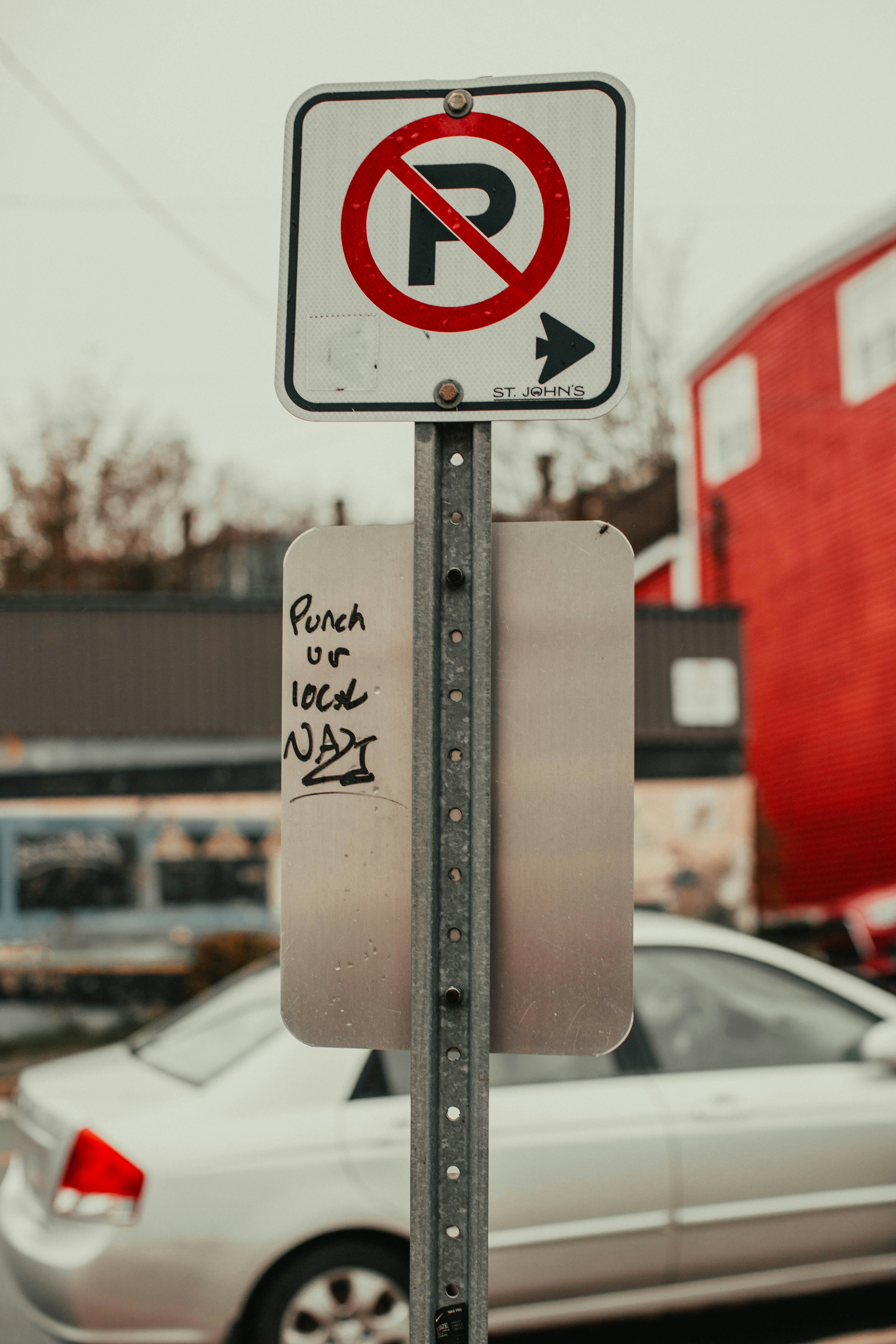 No Parking Sign Over a Graffiti-Tagged Panel in an Urban Alley