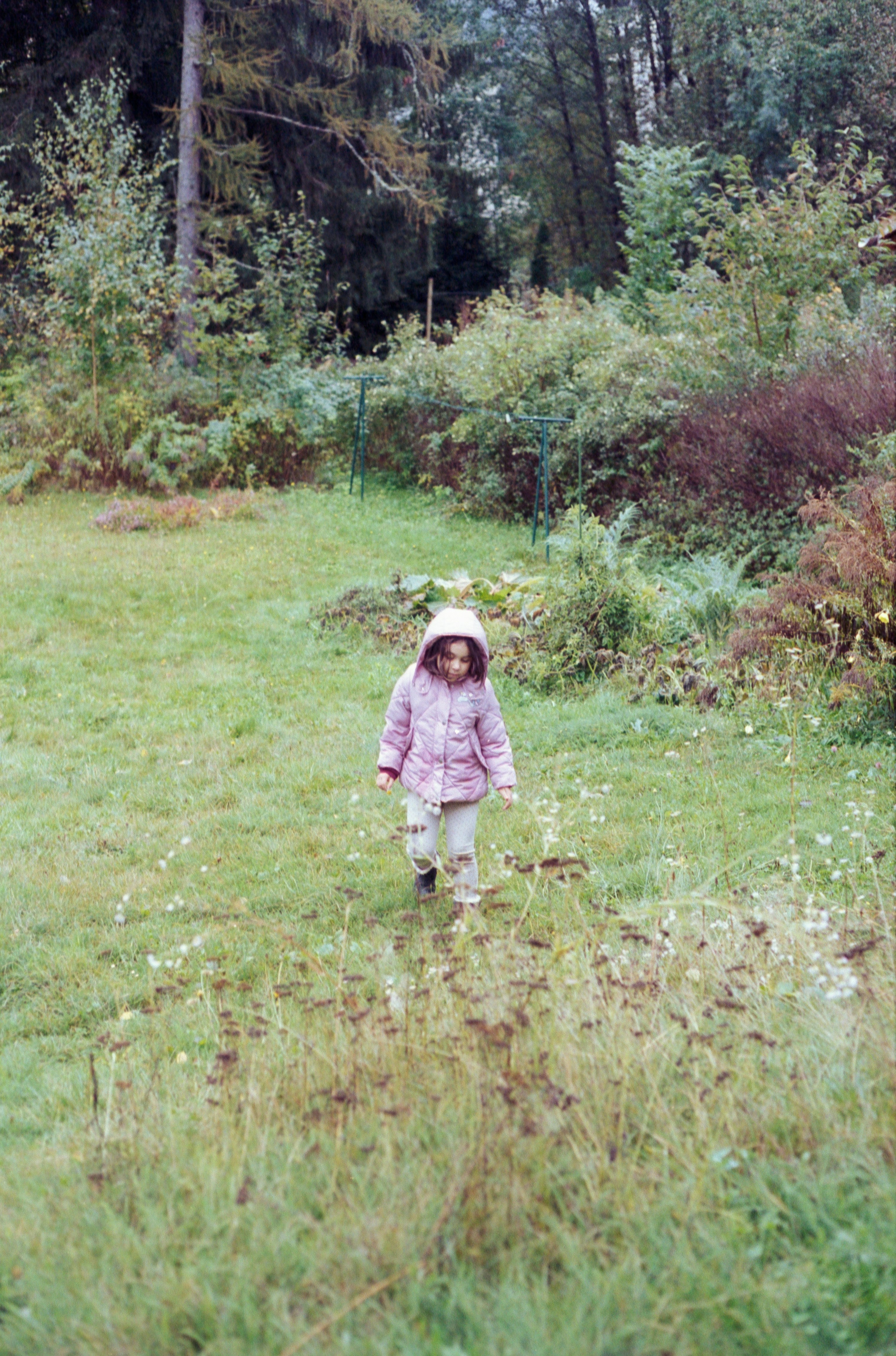 girl in pink dress walking on green grass field during daytime