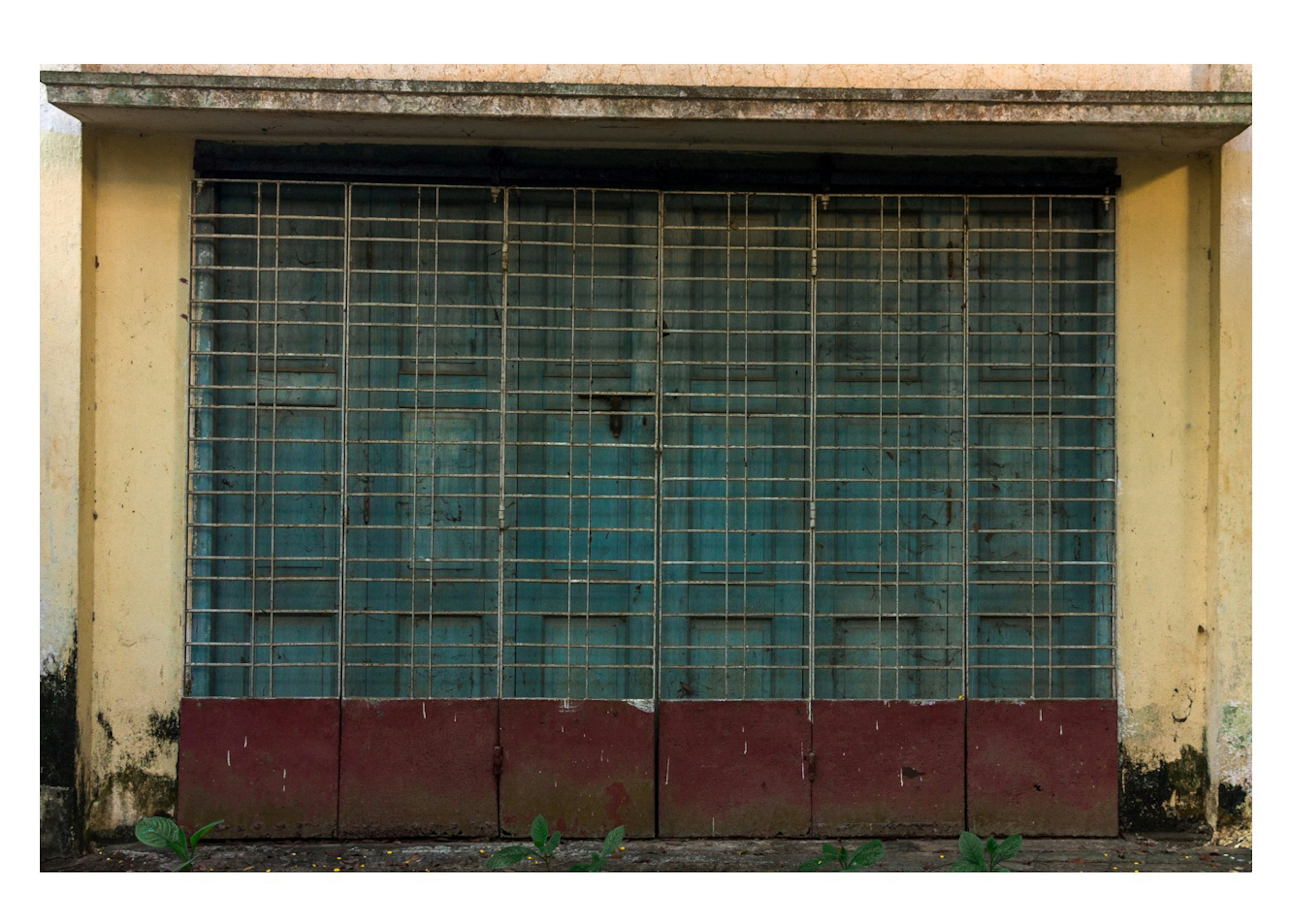 Rusty metal grating covers a weathered doorway, hinting at stories untold and memories lost. The muted colors evoke a sense of nostalgia.