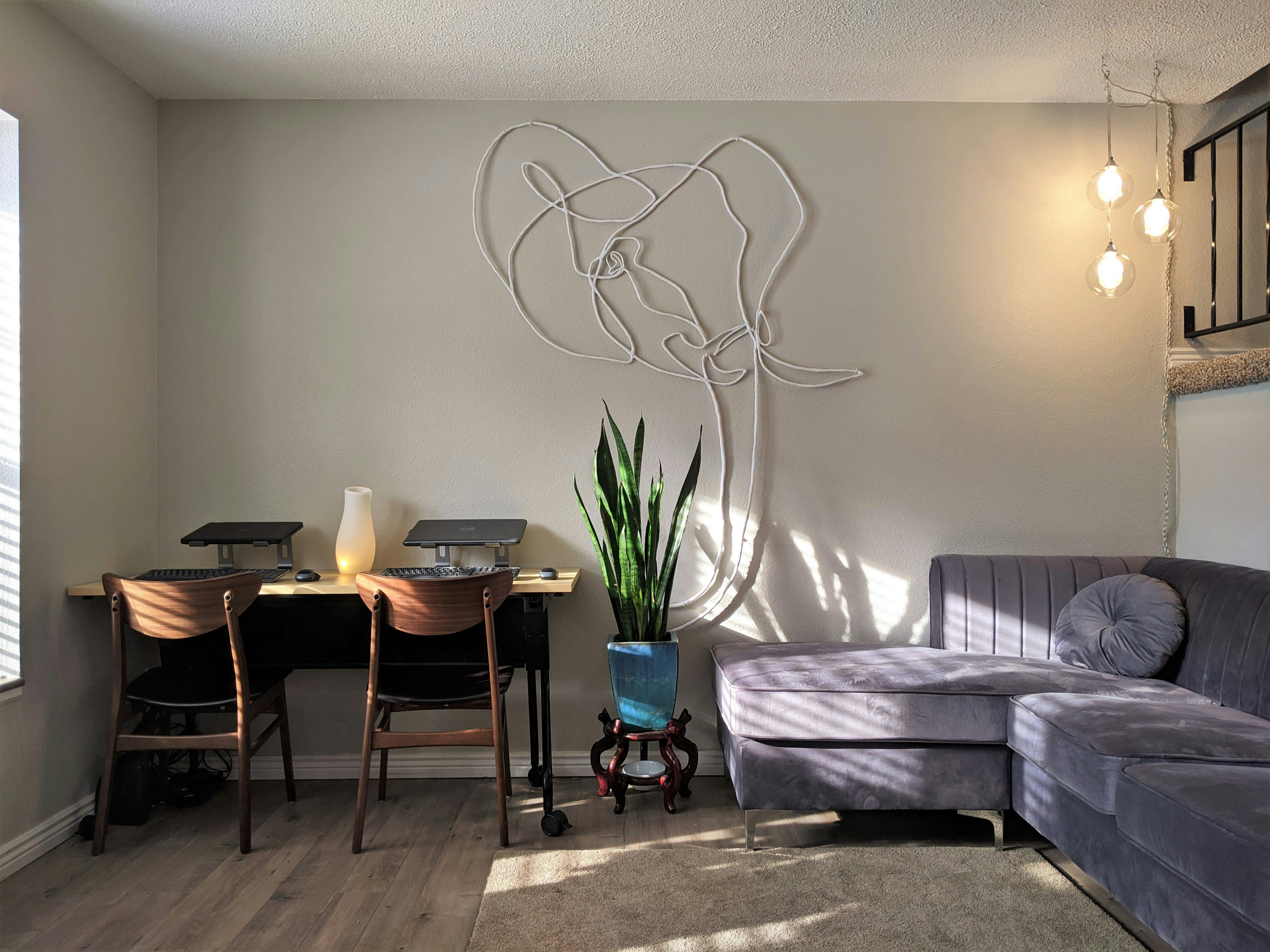 Sunlit Modern Living Room: Wire Wall Art, Verdant Plant, and a Cozy Gray Sofa