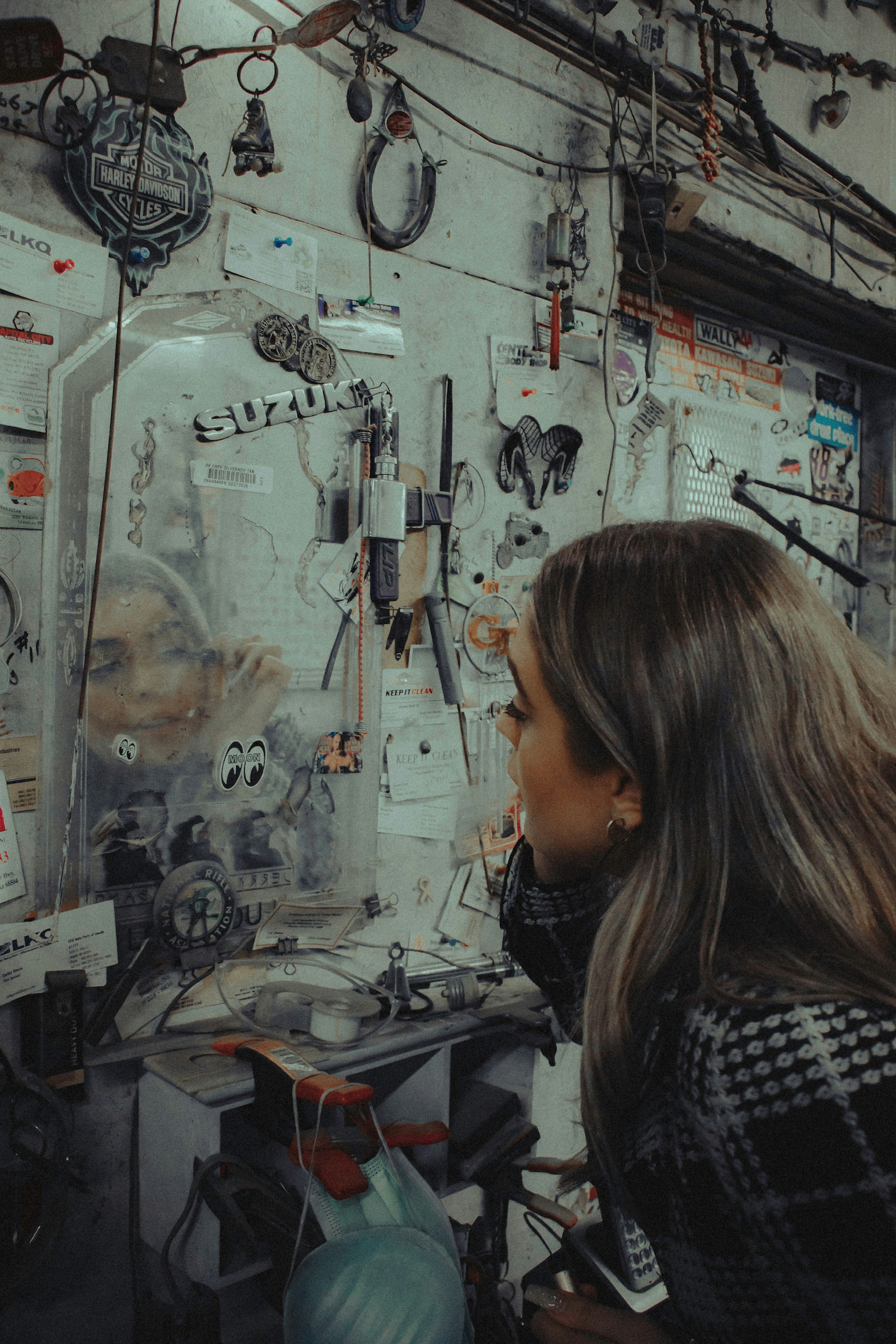 Portrait in a cluttered workshop: a woman studying a motorcycle display
