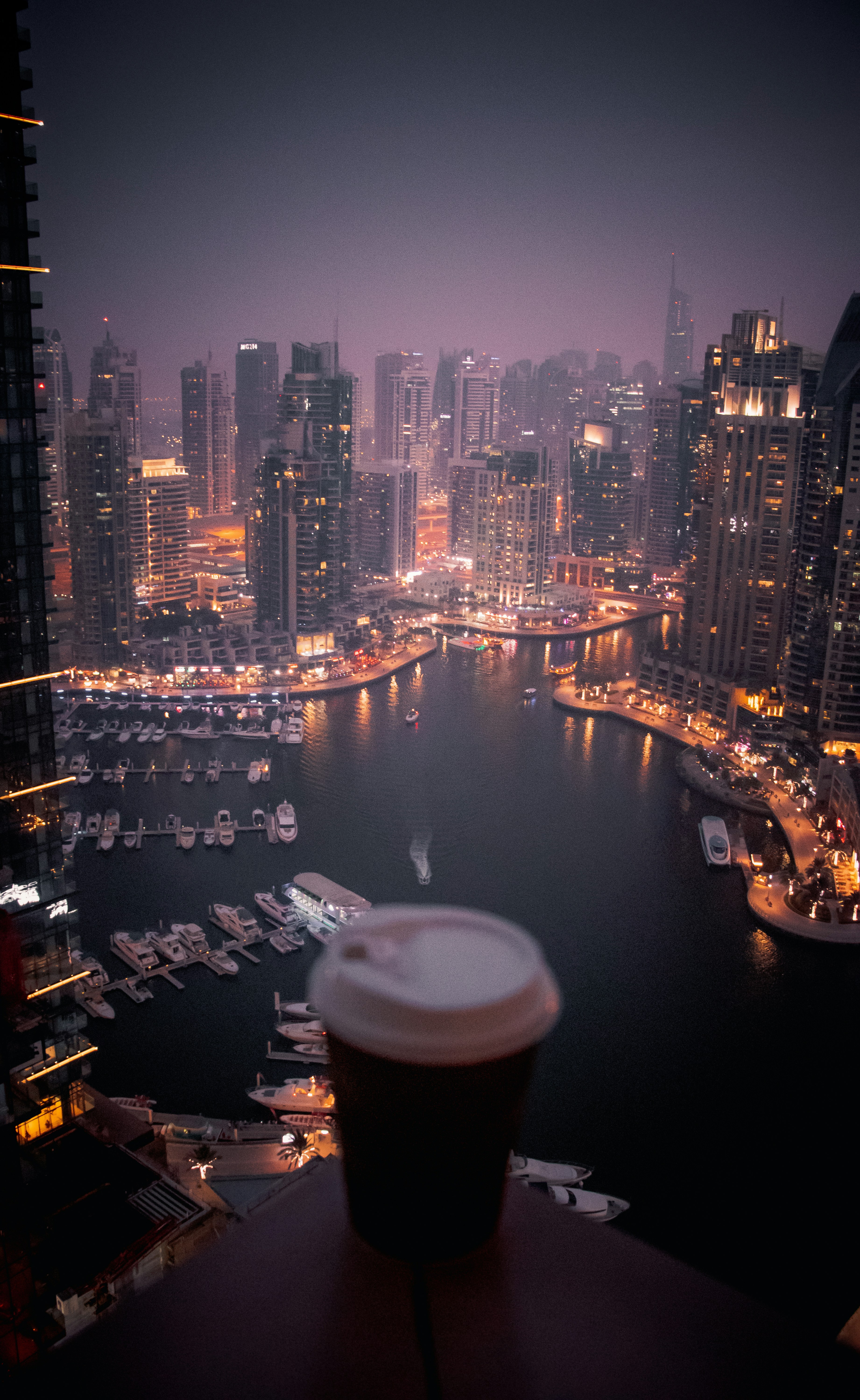 Night Marina Overlook: A Coffee Cup Foreground Framing a Dreamy Urban Basin