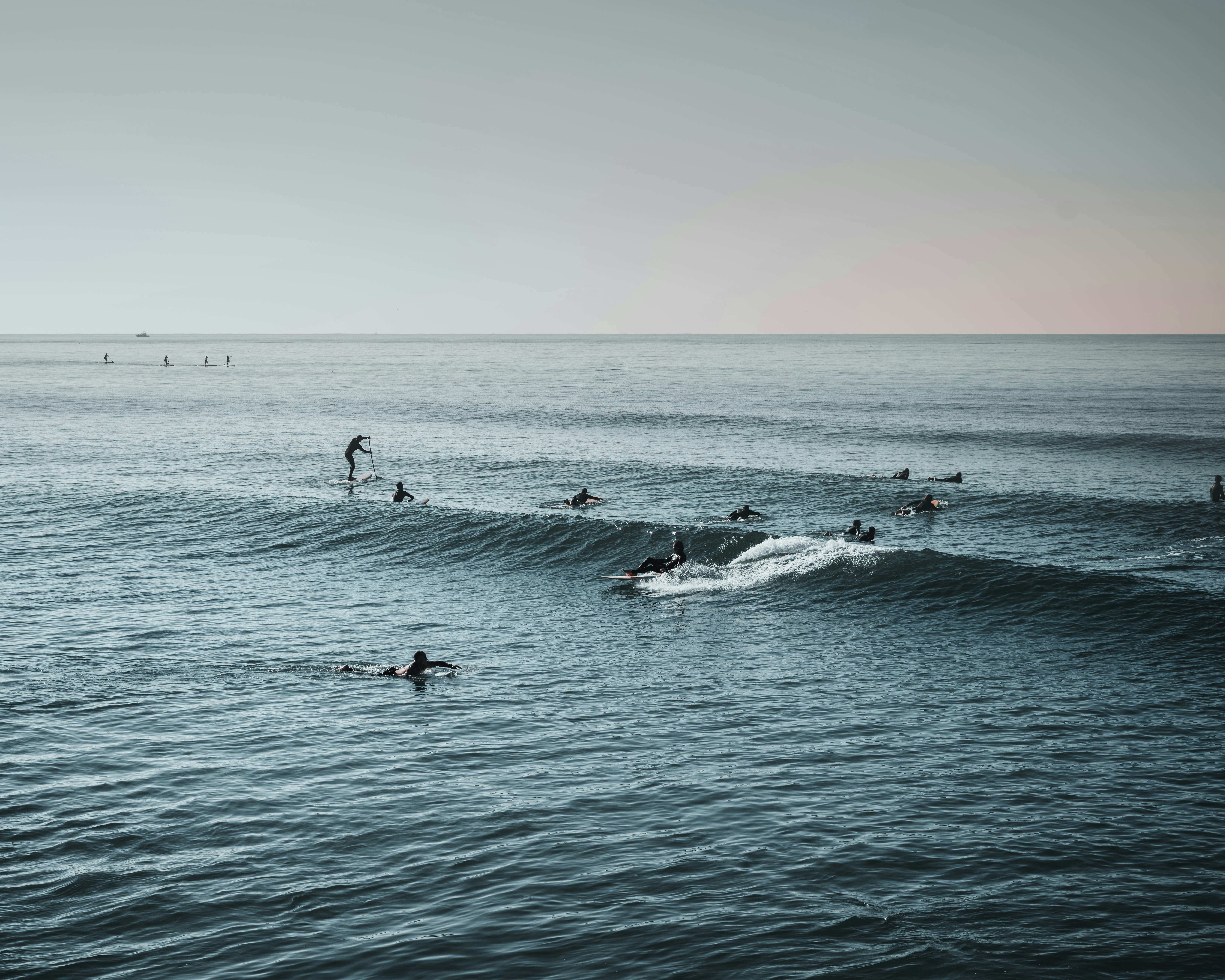 Surfers skillfully navigating the rolling waves under a serene sky. The scene captures the essence of a vibrant coastal lifestyle.