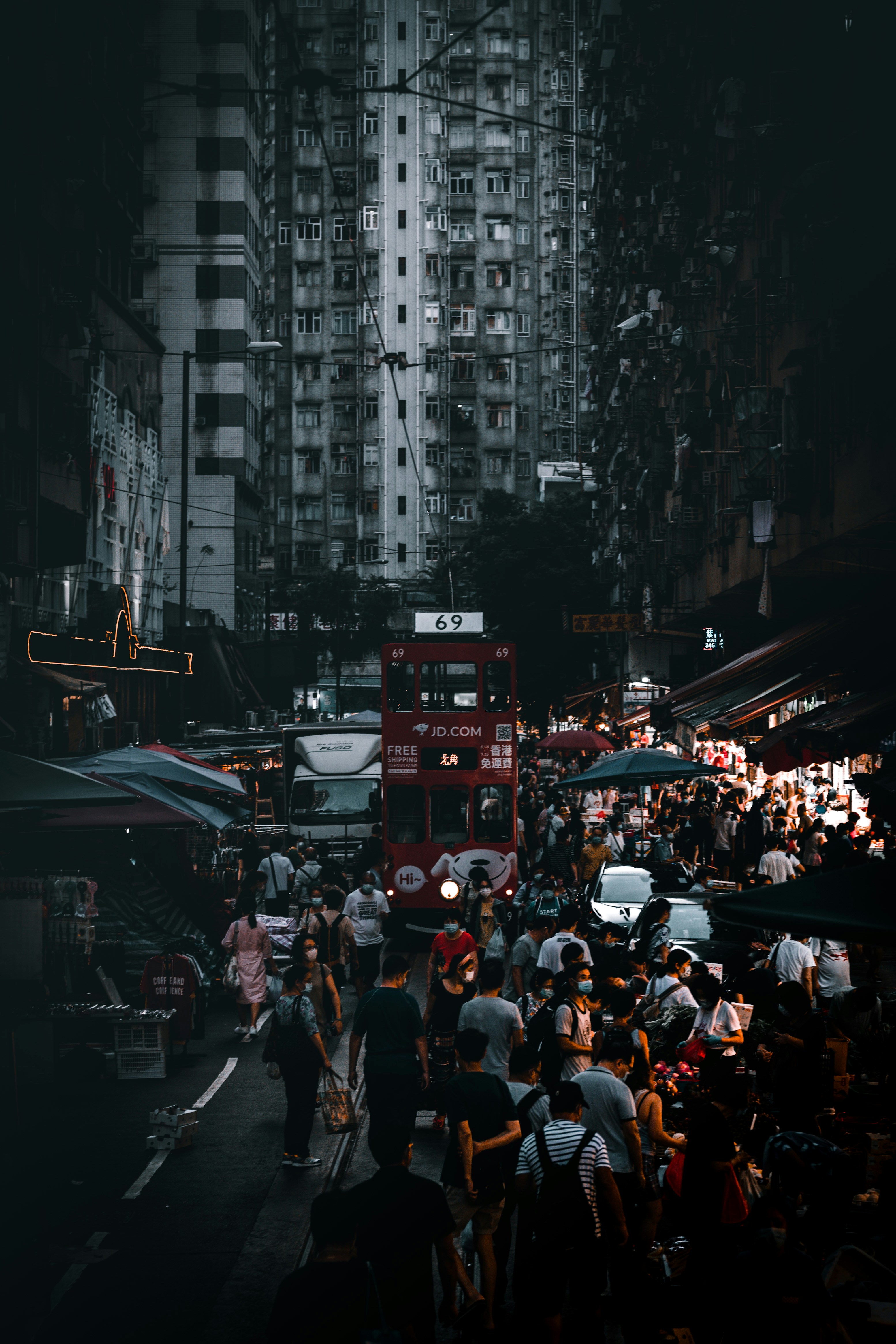 Bustling street market scene in a densely populated urban area, showcasing vibrant stalls and a crowd of people navigating the narrow streets.