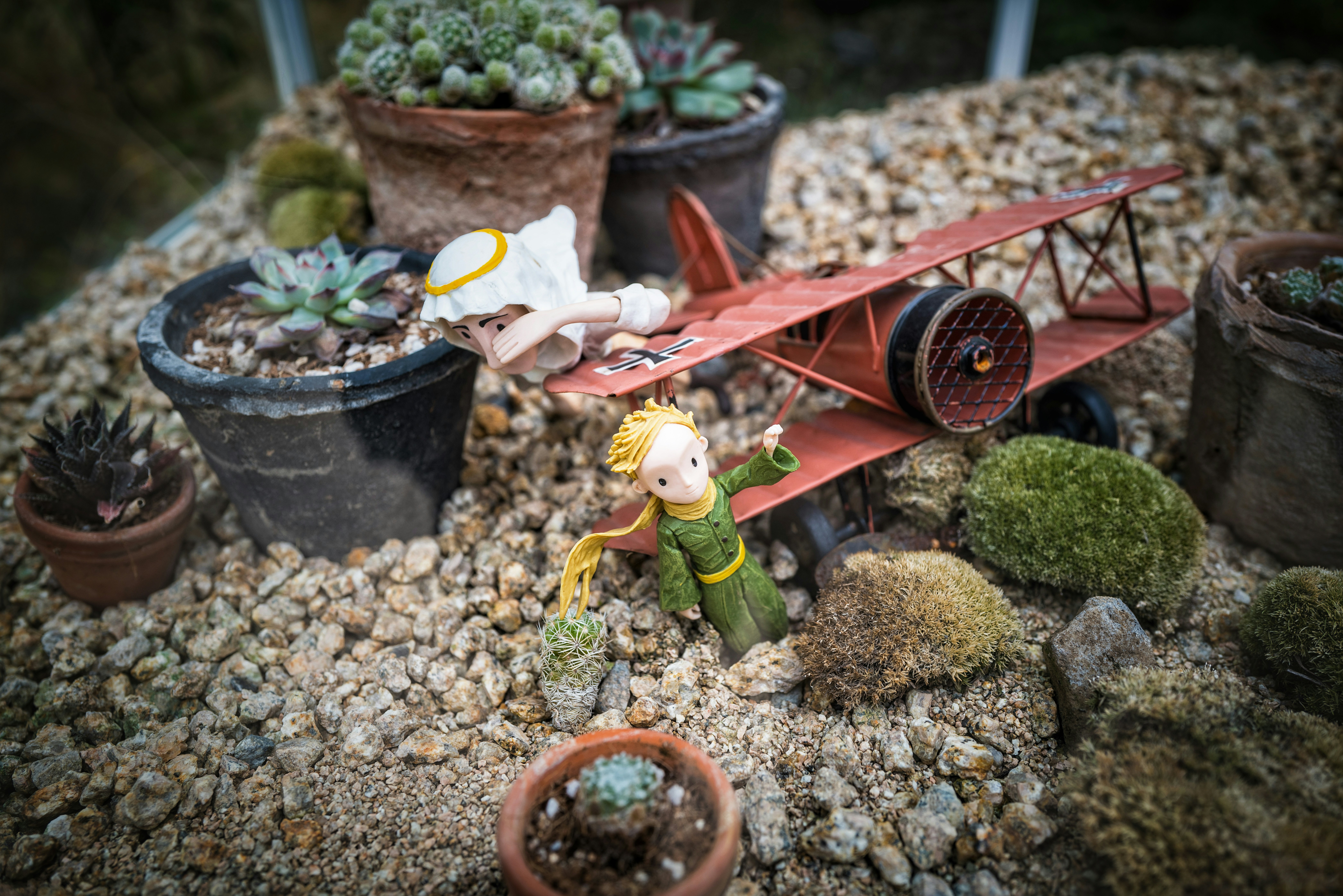 Tiny aviators on a gravel runway: a garden diorama with a red biplane