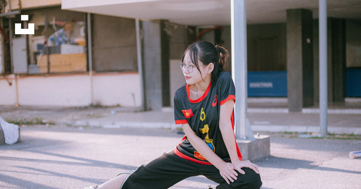 灰色のコンクリートの床に座っている黒と赤のナイキのシャツと黒のズボンを着た女性の写真 Unsplashのhọc Viện Kỹ Thuật