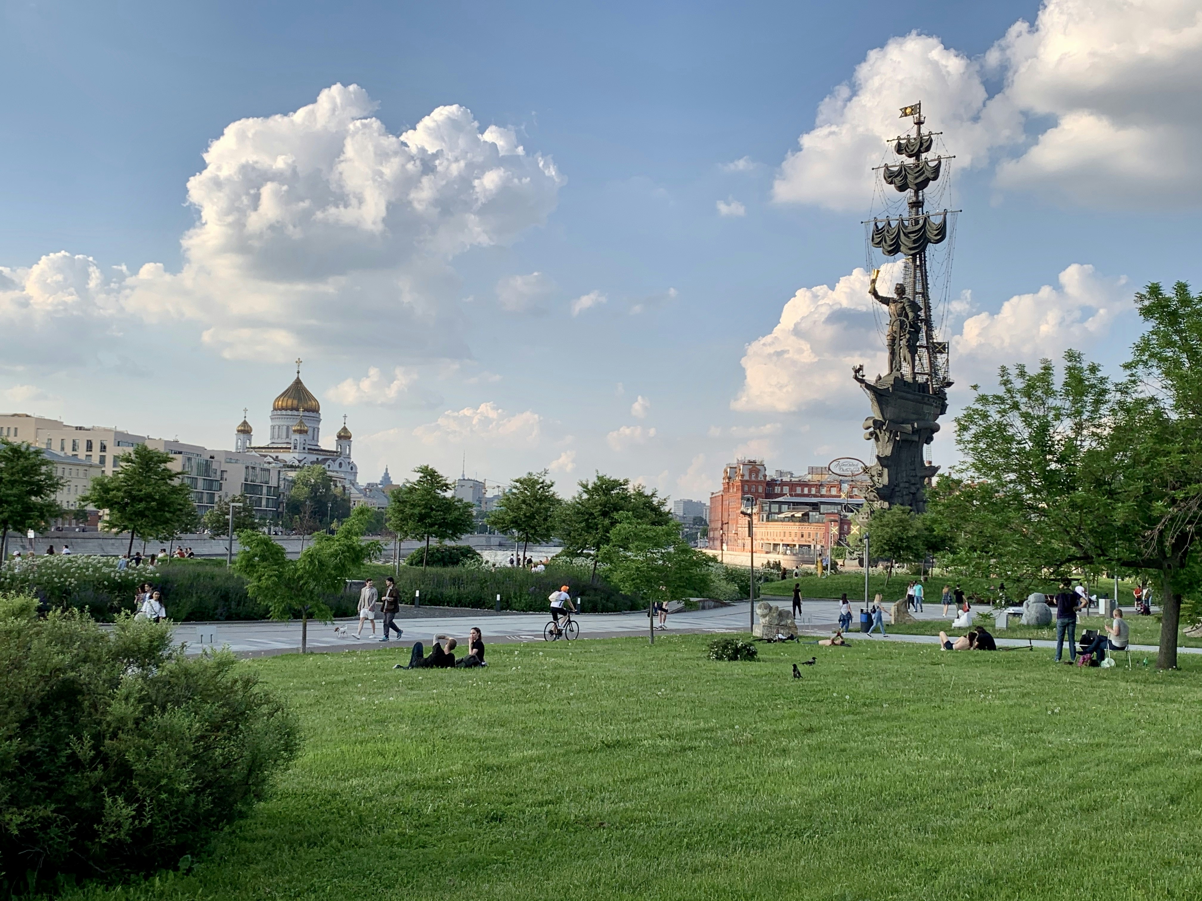 Visitors enjoying a leisurely day in a park, with a prominent monument and cityscape in the background. The scene captures the harmony of nature and urban life.