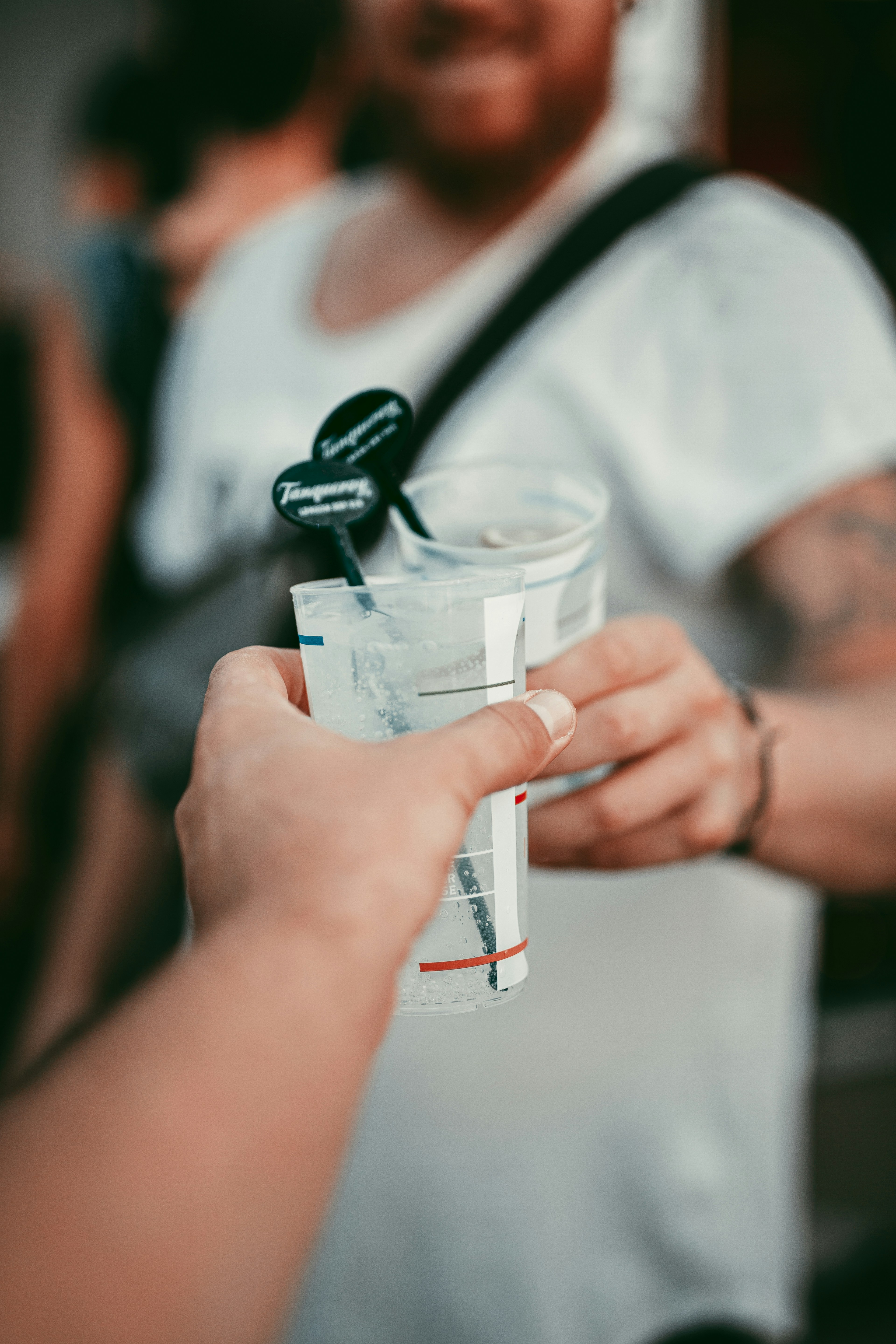 person holding clear plastic cup with black plastic straw