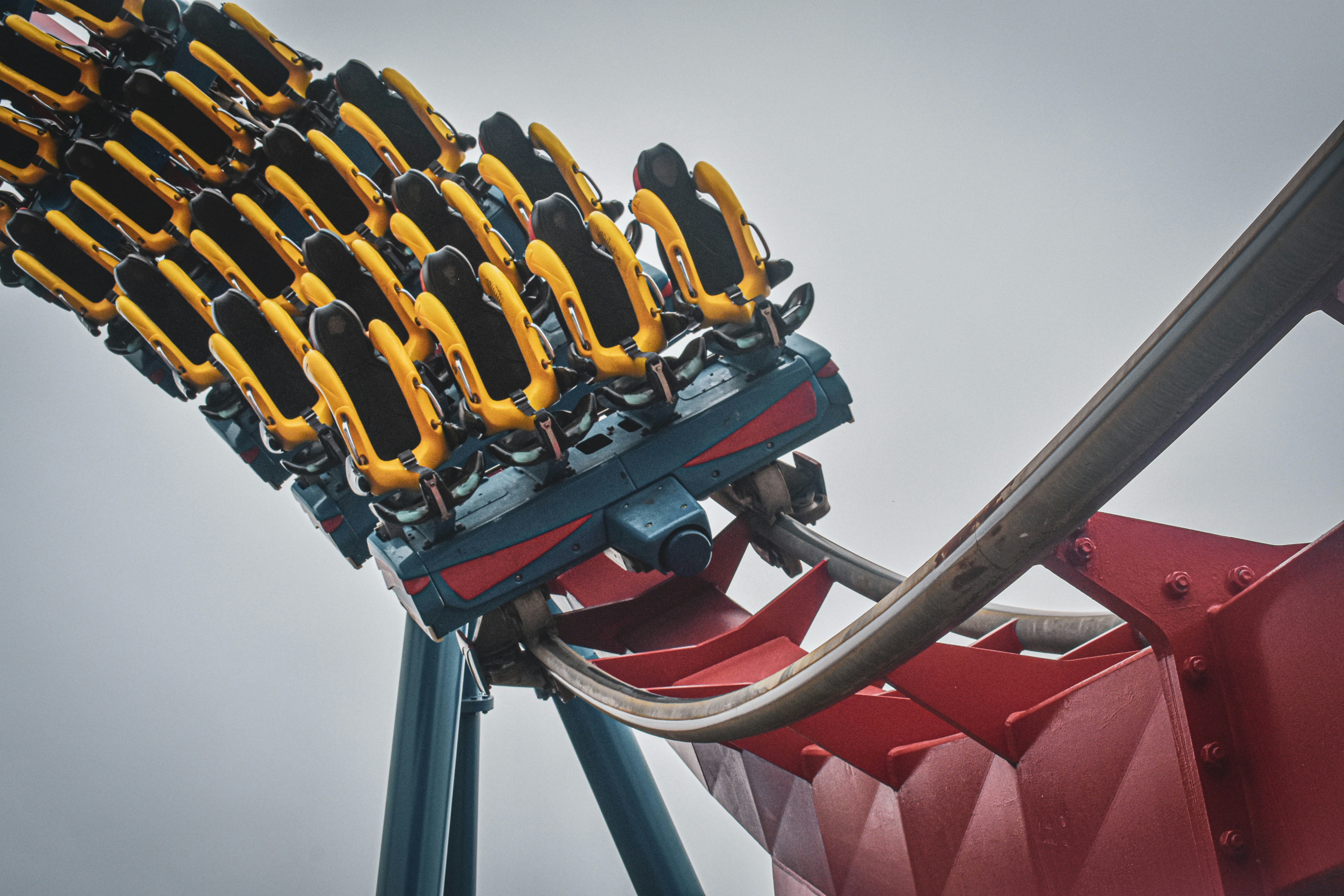 A close-up view of a roller coaster's train poised at the apex of a loop, showcasing the vibrant yellow seats against a backdrop of metallic structure.