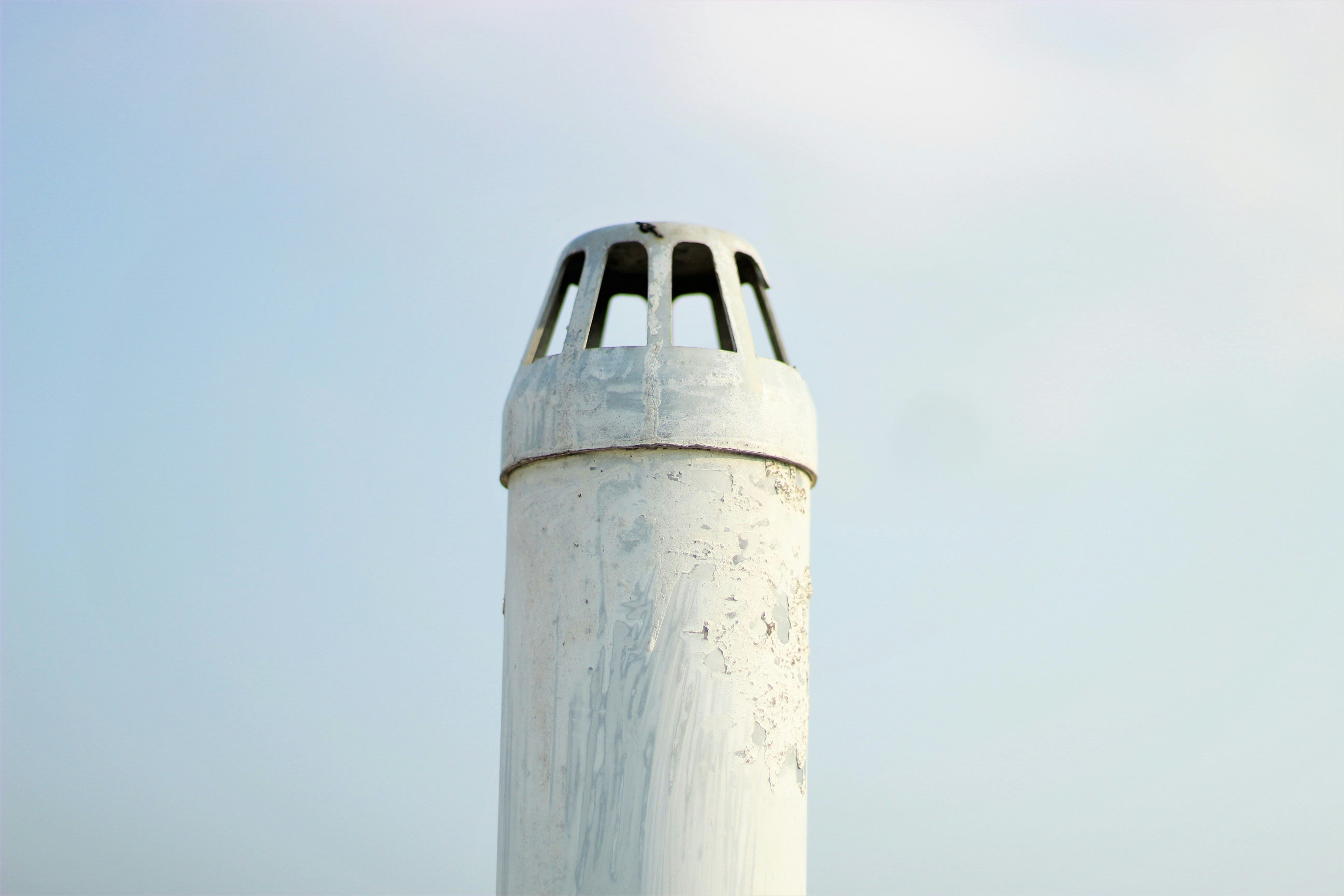 Lattice-Capped Chimney Piercing a Pale Blue Sky