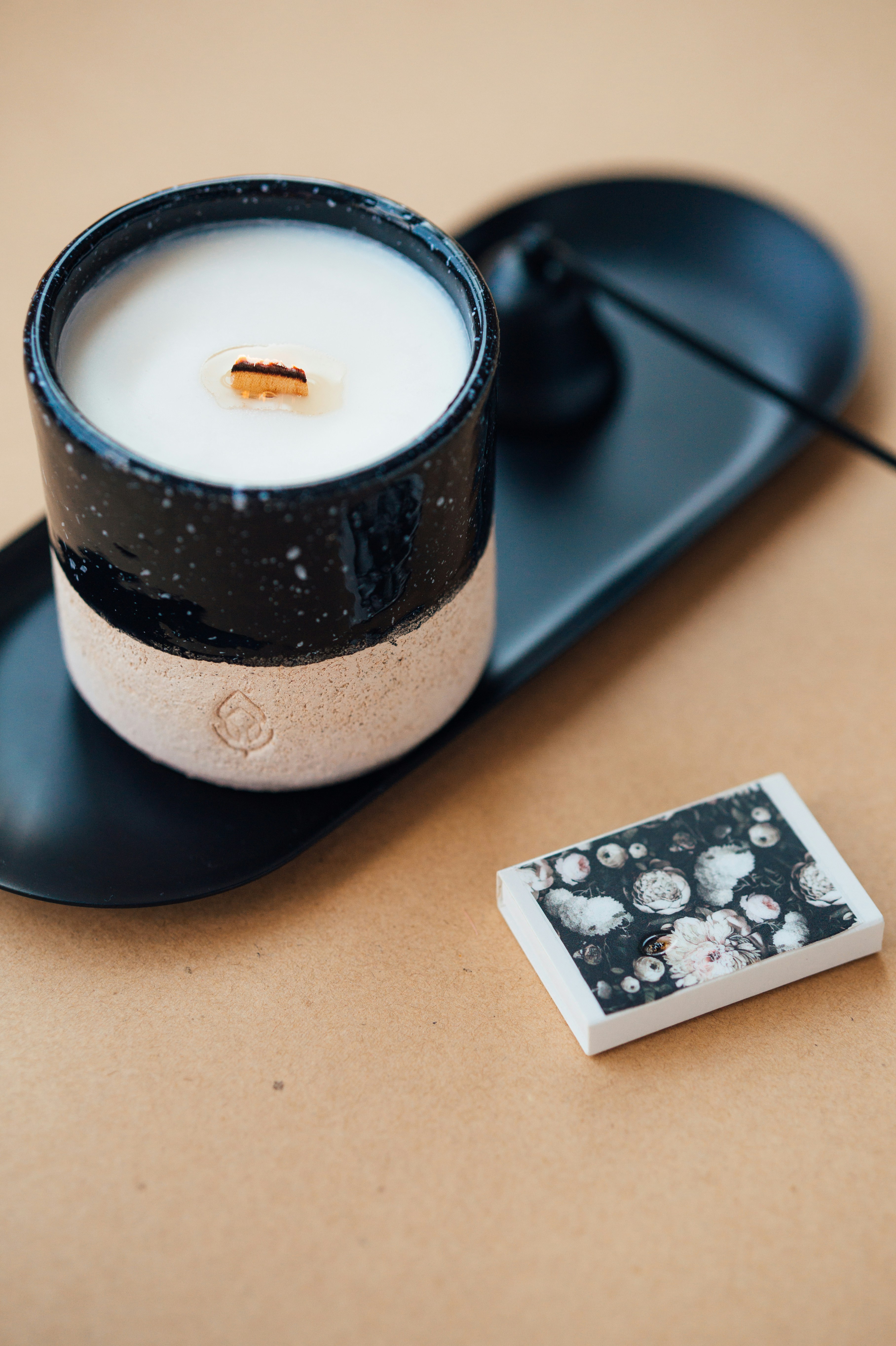 Two-Tone Ceramic Candle with a Tiny Wick and Floral Matchbox on a Warm Brown Surface