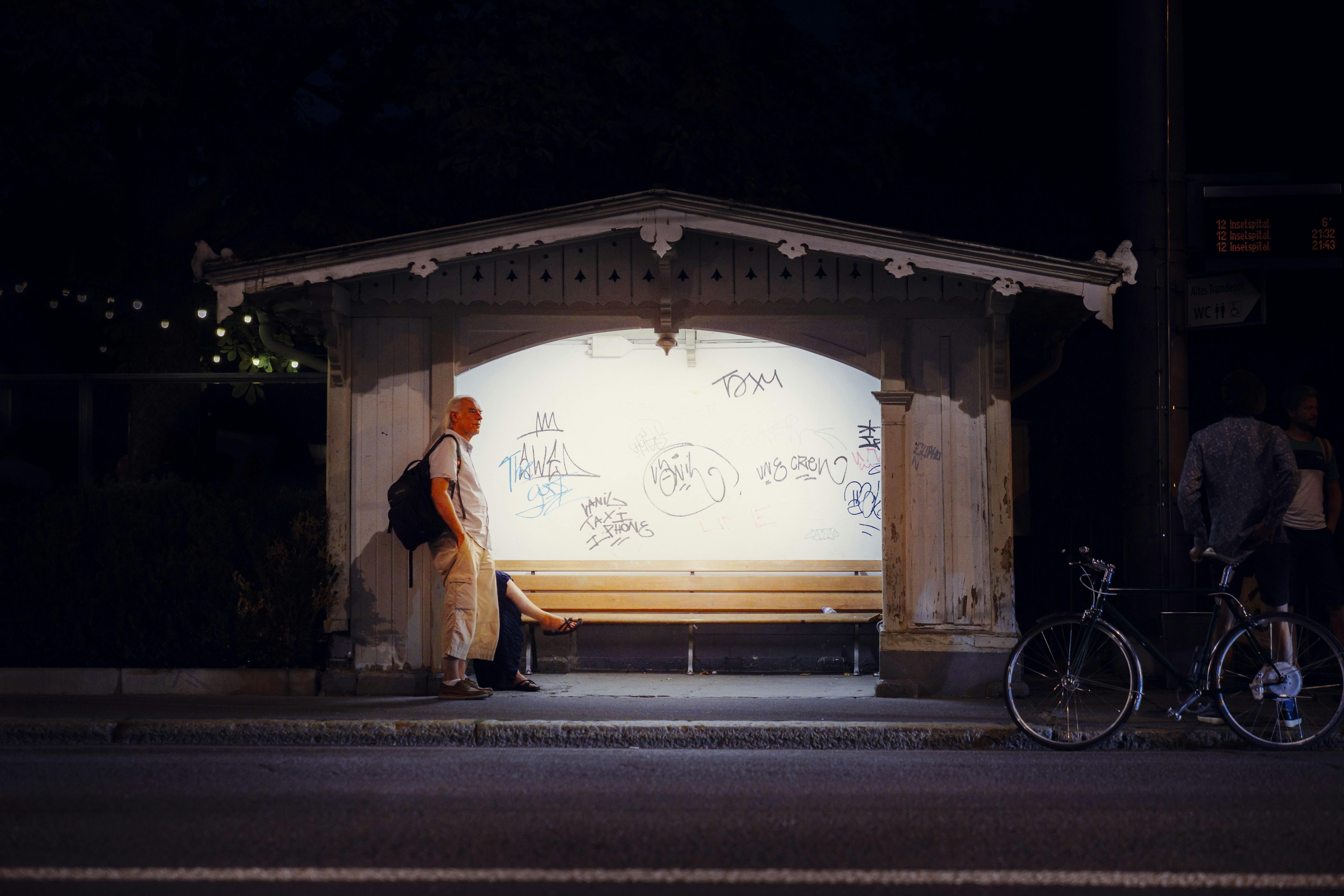 Man waiting at a bus station at night in Bern, Switzerland.