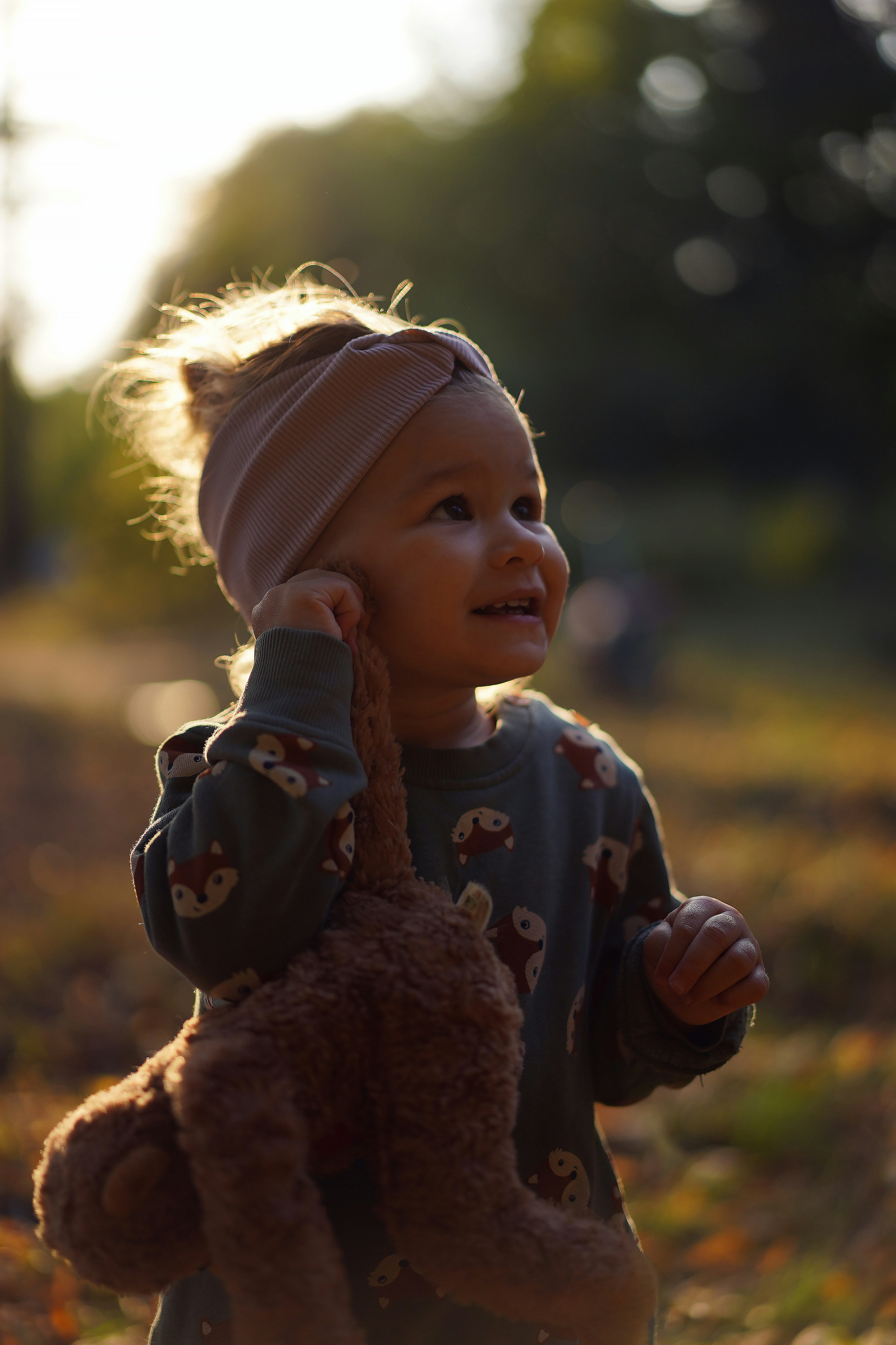 Amber Hour Whisper: A toddler in warm backlight with a plush companion