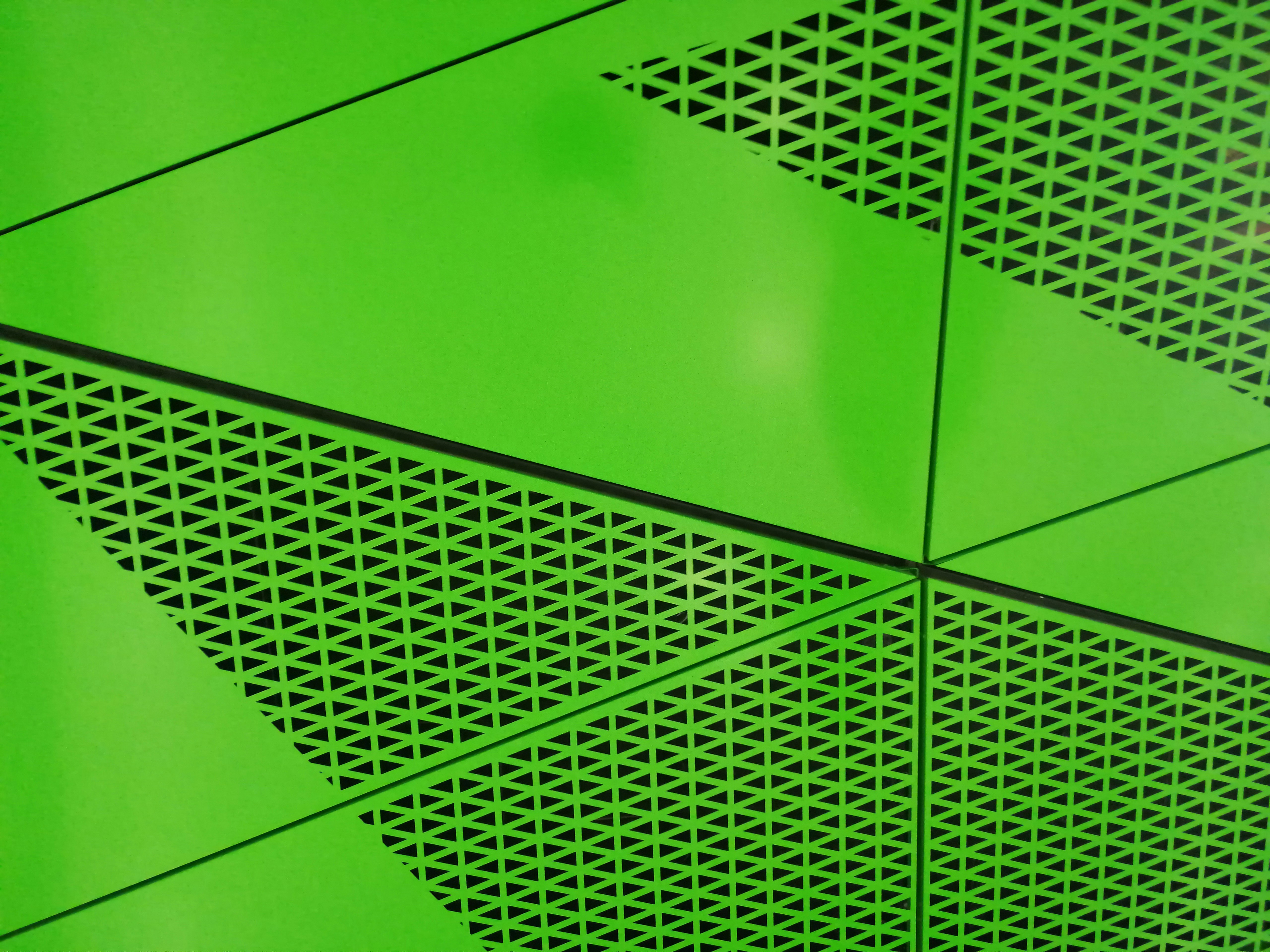 Abstract pattern of green panels with intricate triangular cutouts creating a dynamic visual texture.
