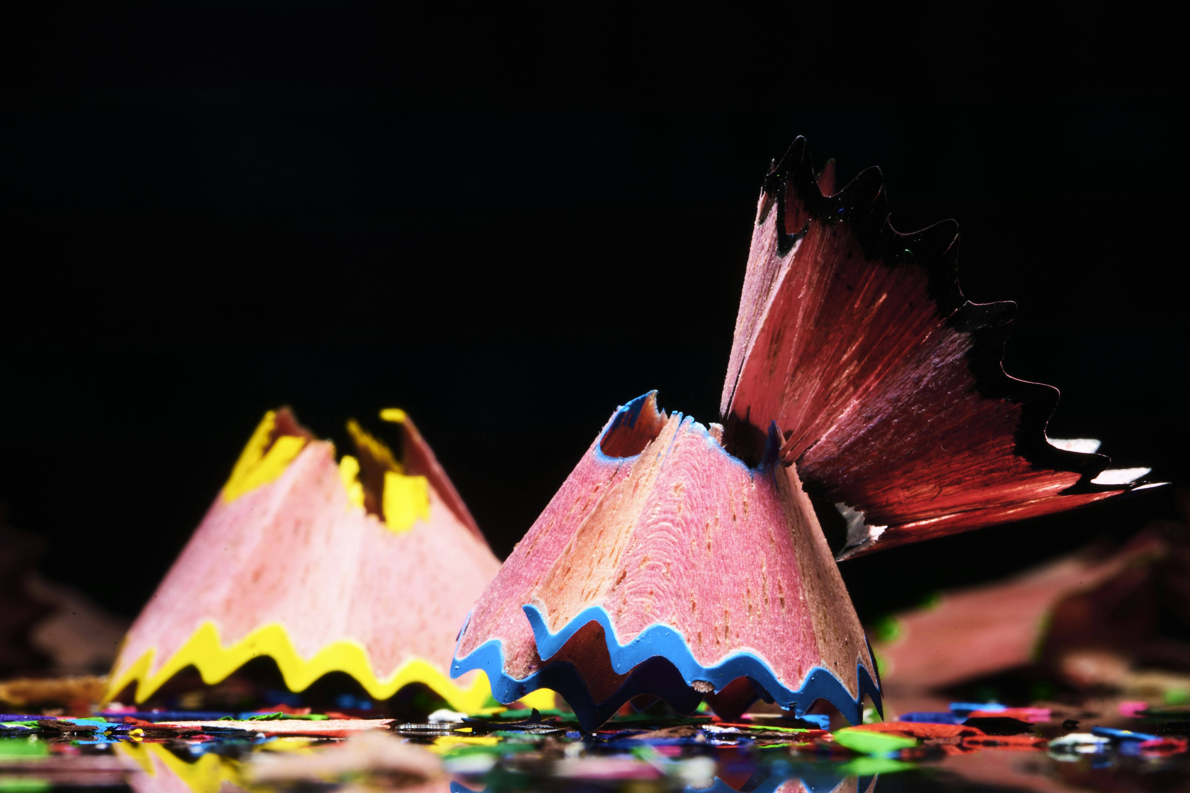 Crimson Curl and Neon Rings: Macro Pencil Shavings on a Reflective Stage