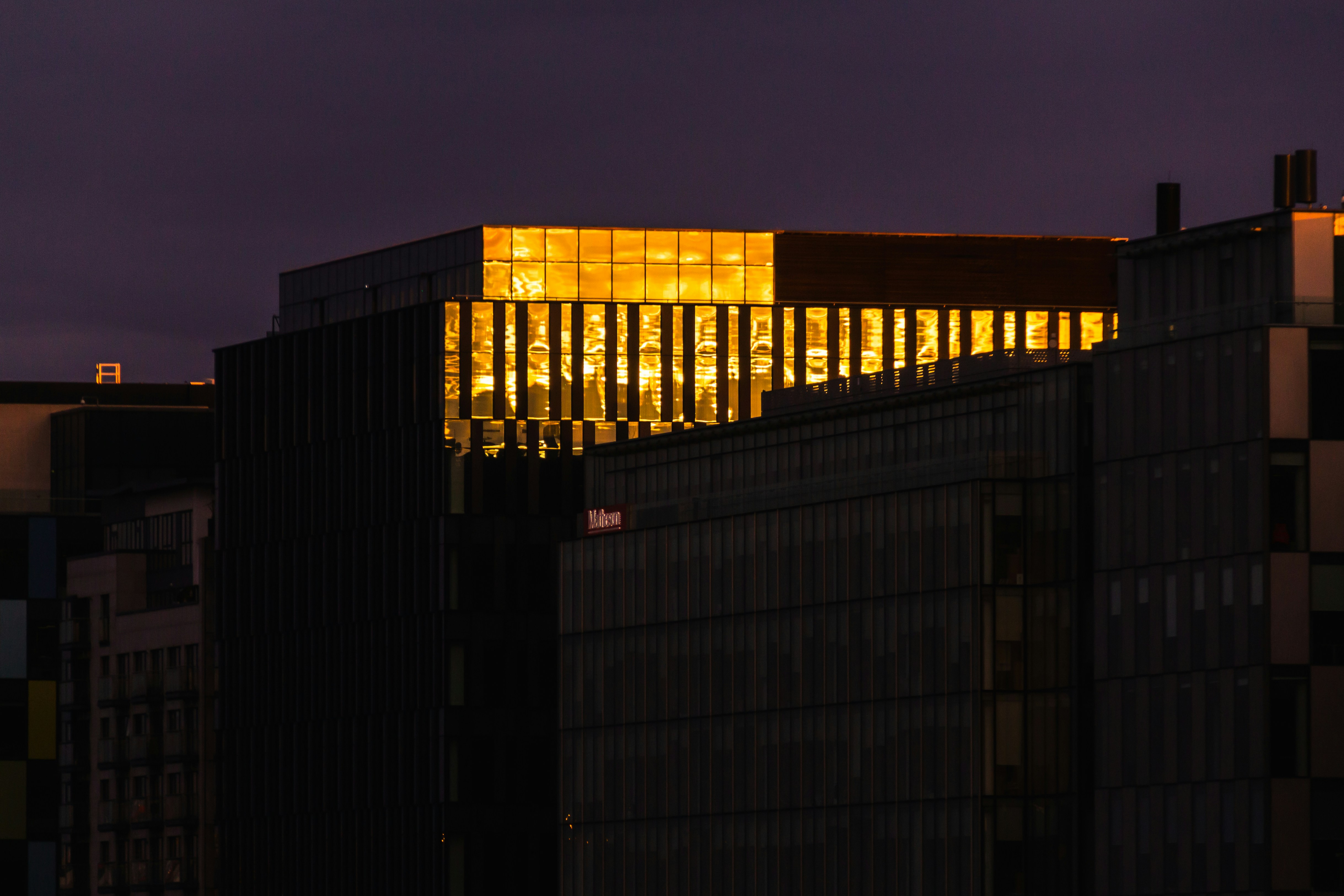 Gold Crown at Dusk: Sunset glow crowns a modern office tower above the city