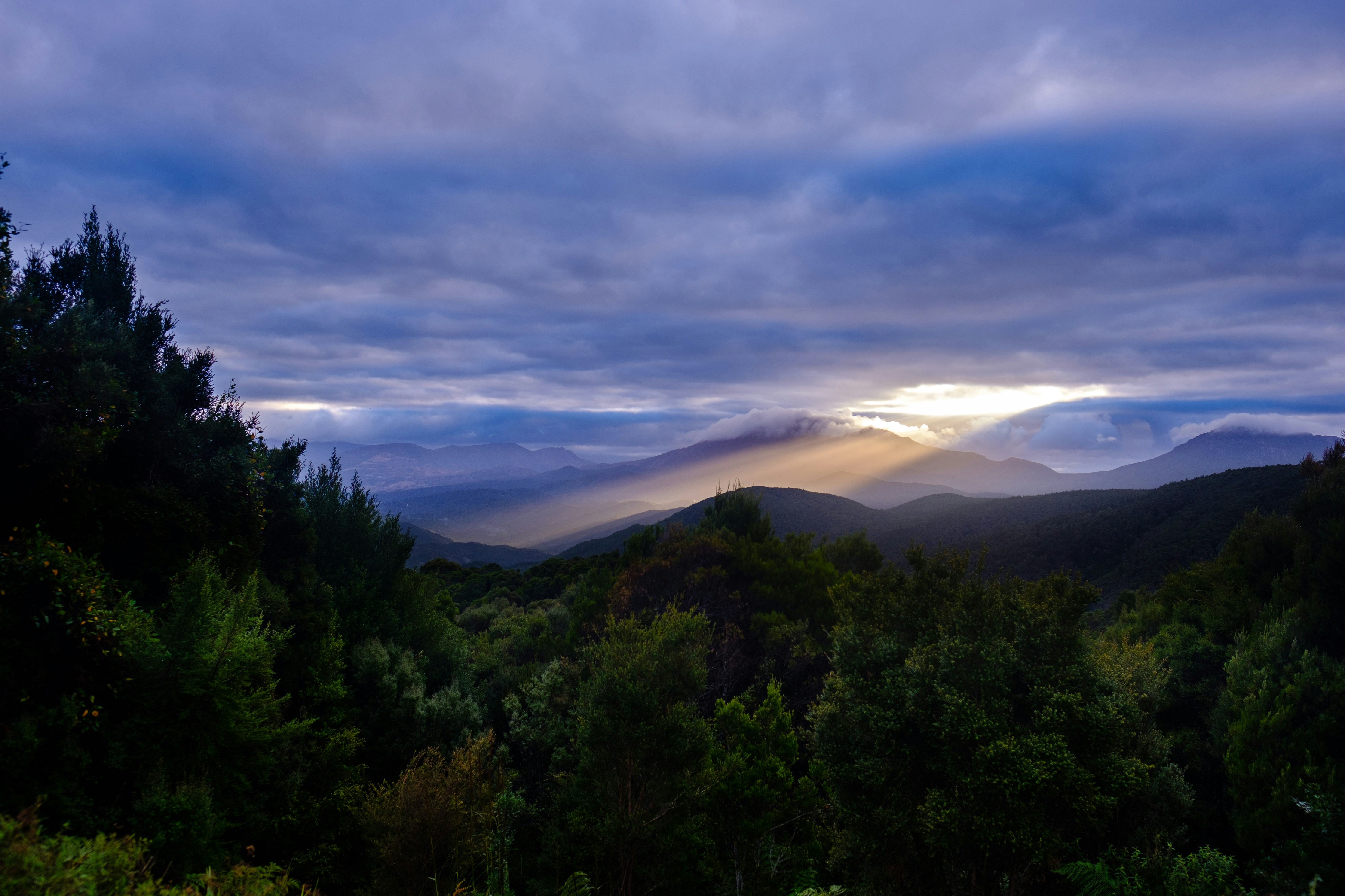 the sun is shining through the clouds over the mountains